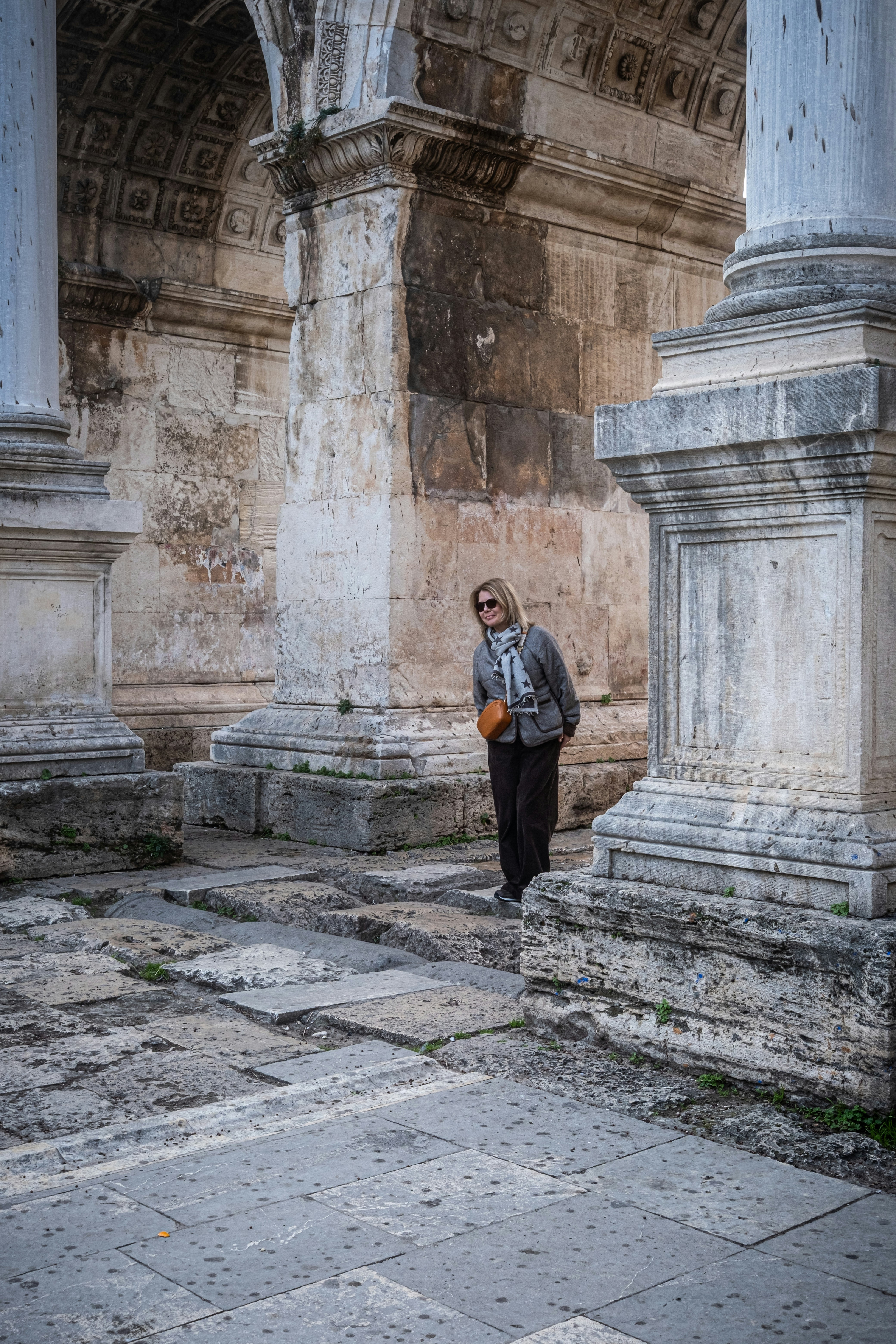 Woman standing near ancient stone ruins and marble columns