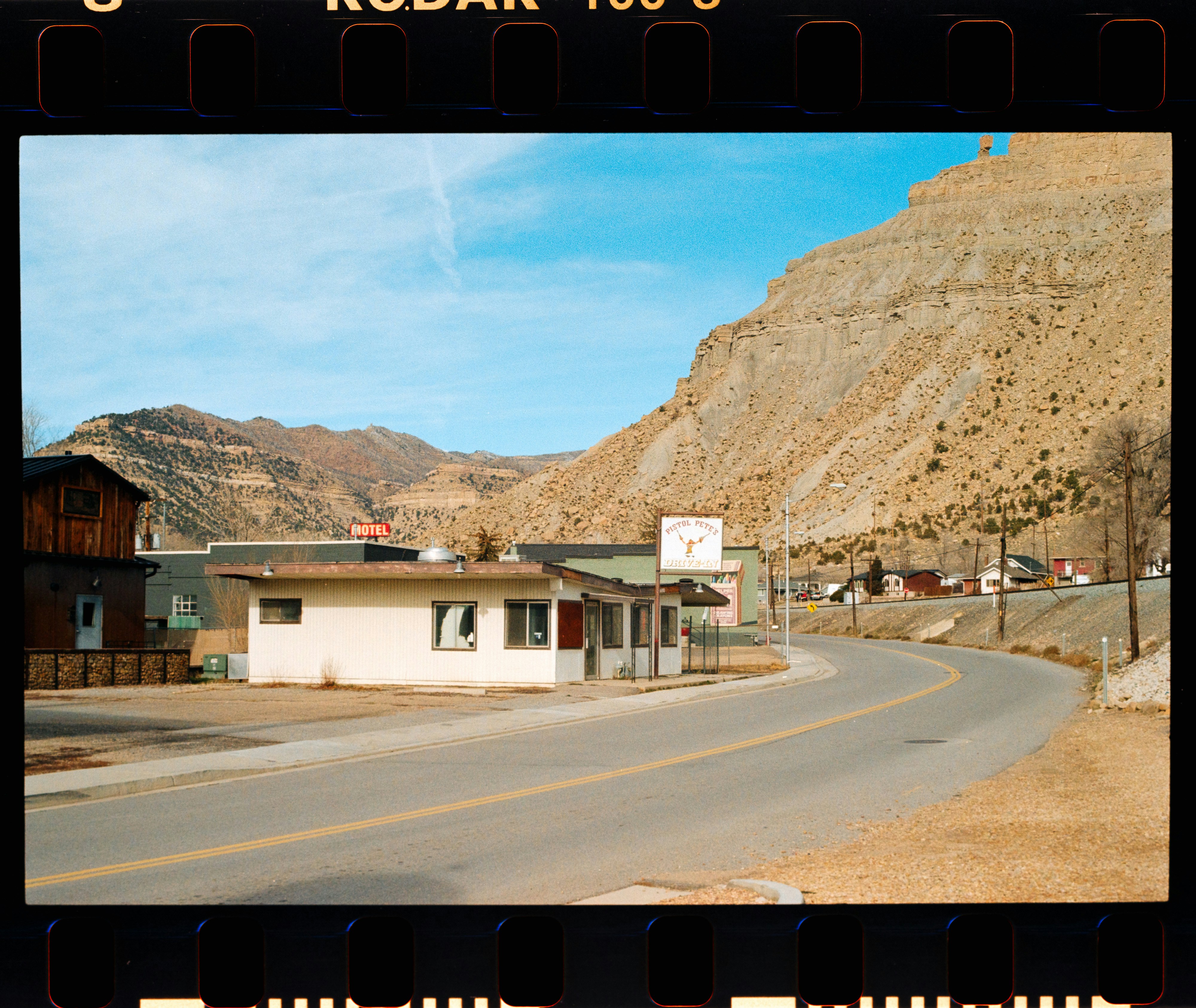 Desert Highway Village at the Base of a Looming Cliff