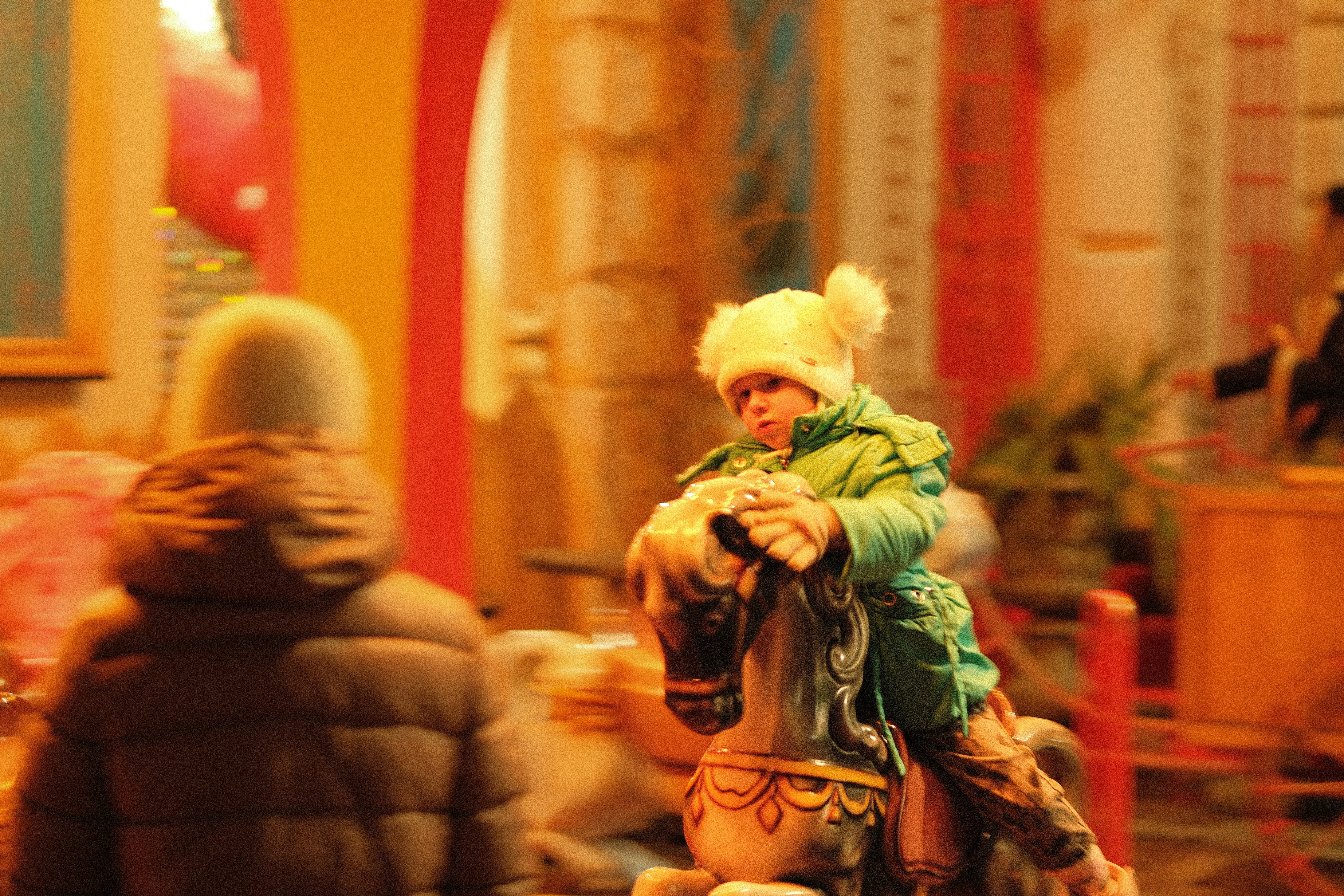 Tiny Rider, Warm Lights: A Child on a Carousel in a Festive Street