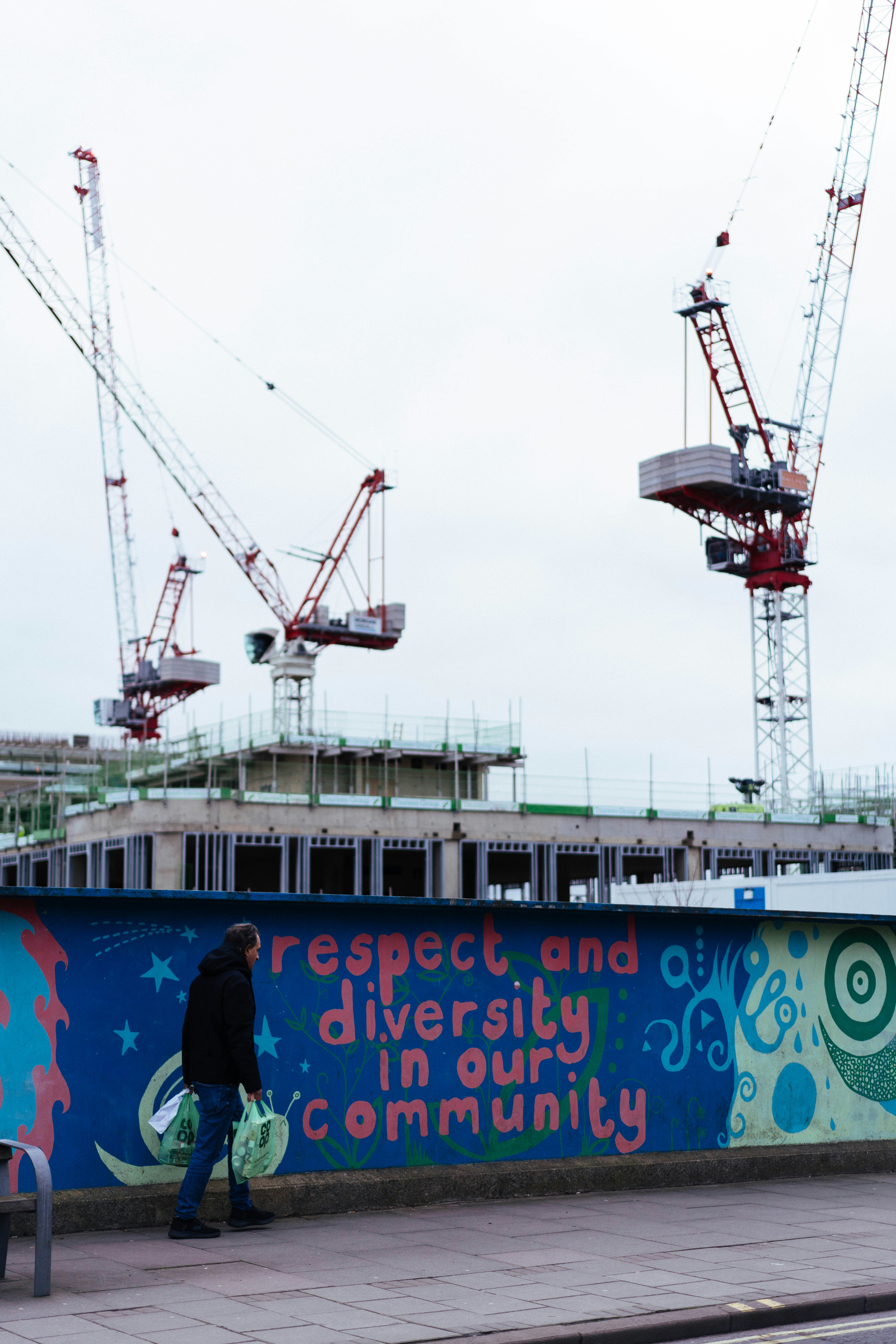 Man walks past mural with cranes in background photo – Free Growth ...
