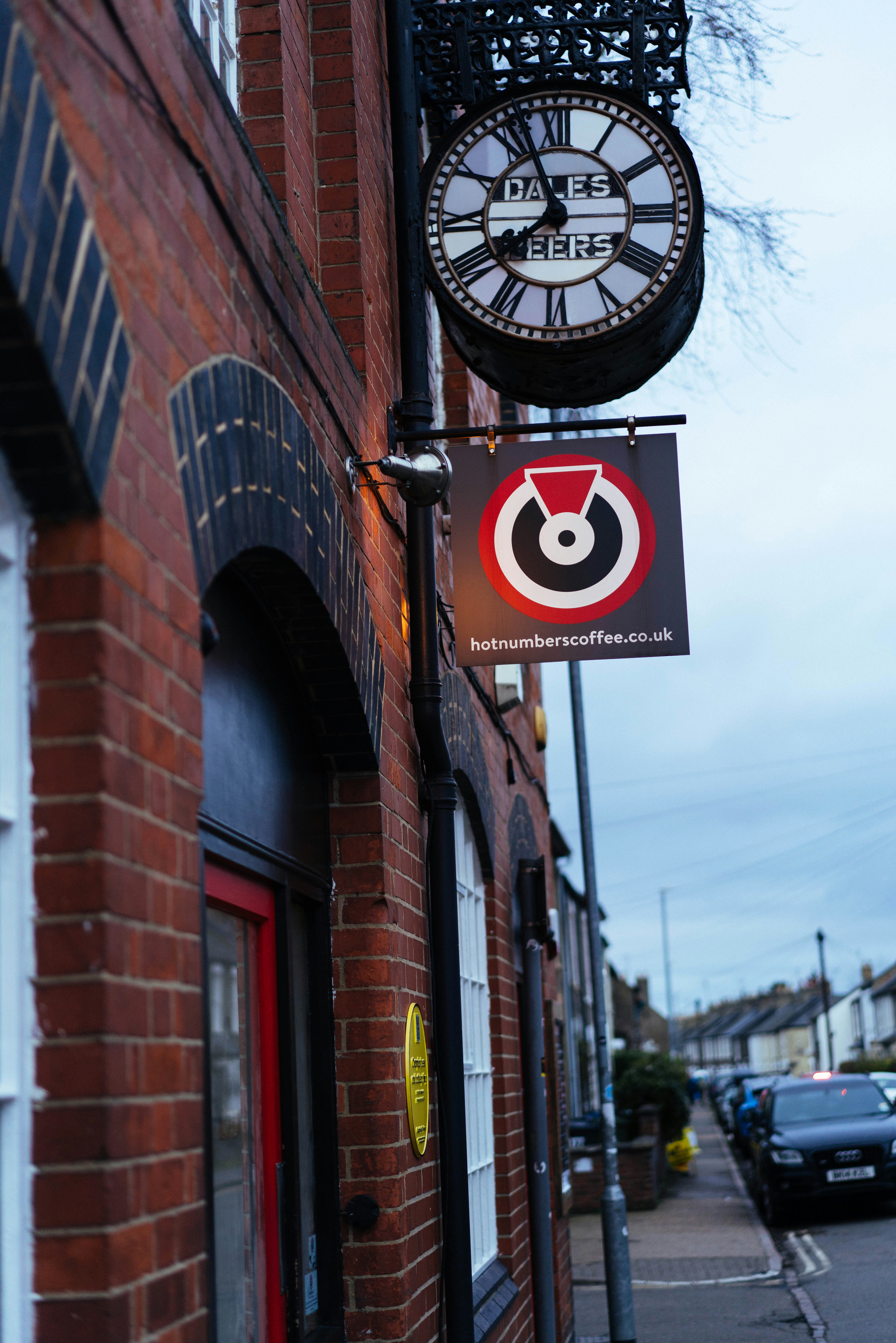 Brick-and-Iron Street: A Clock Banner and Coffee Sign Adorn a Corner