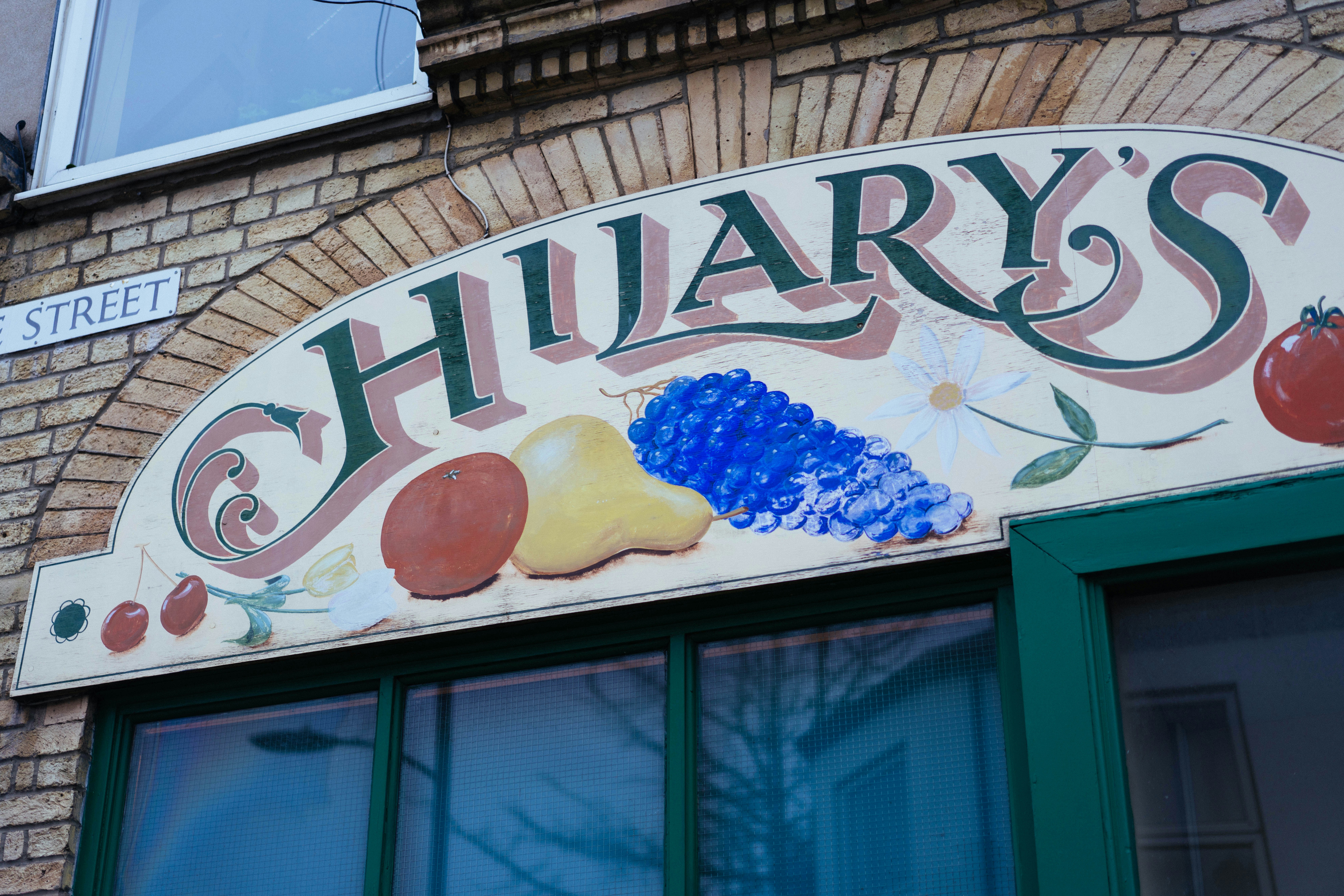 Fruit Signway: A Vintage Market Sign Above Green Doors