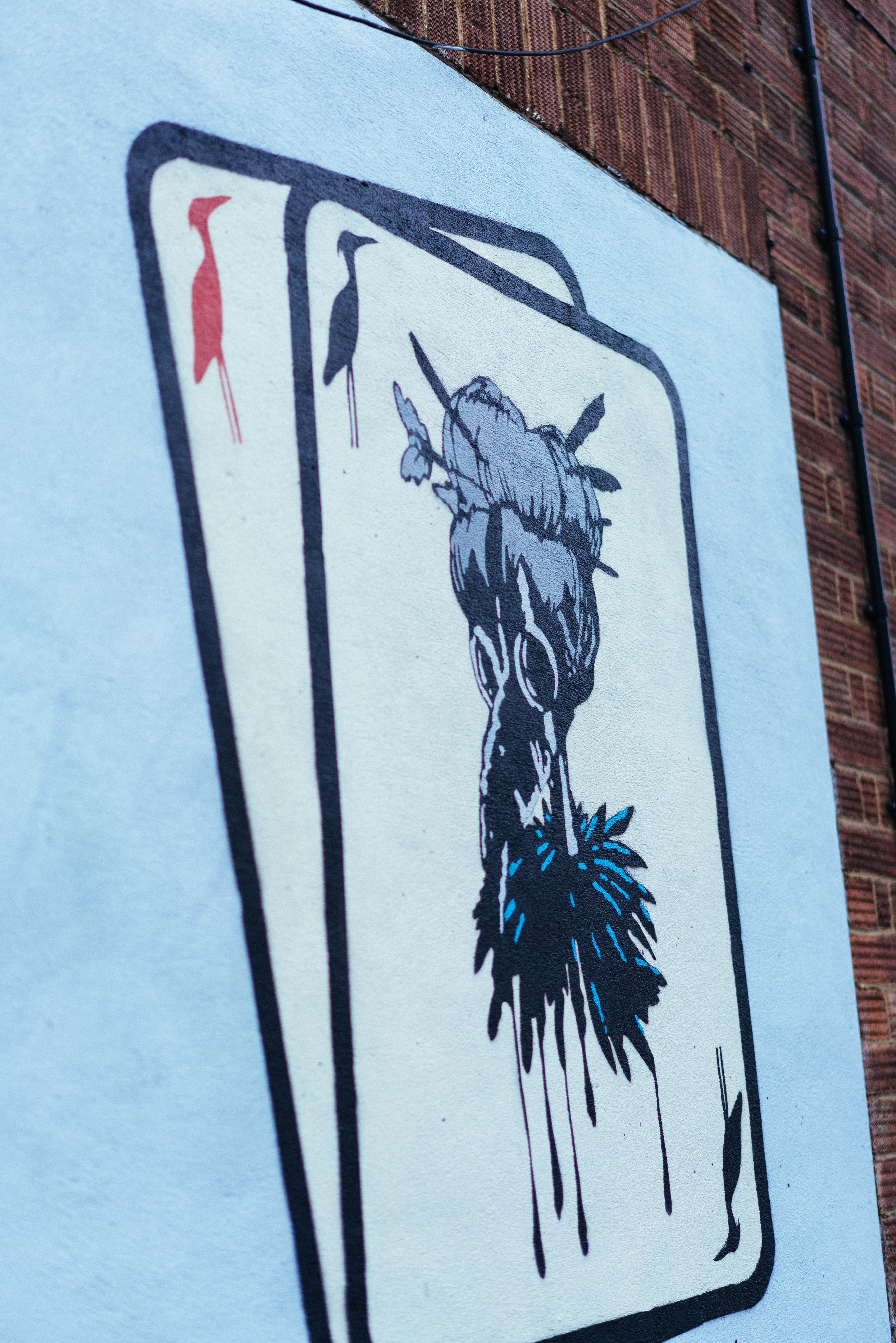 Tall Card Tower: A Blue Silhouette Stache on Brick Wall