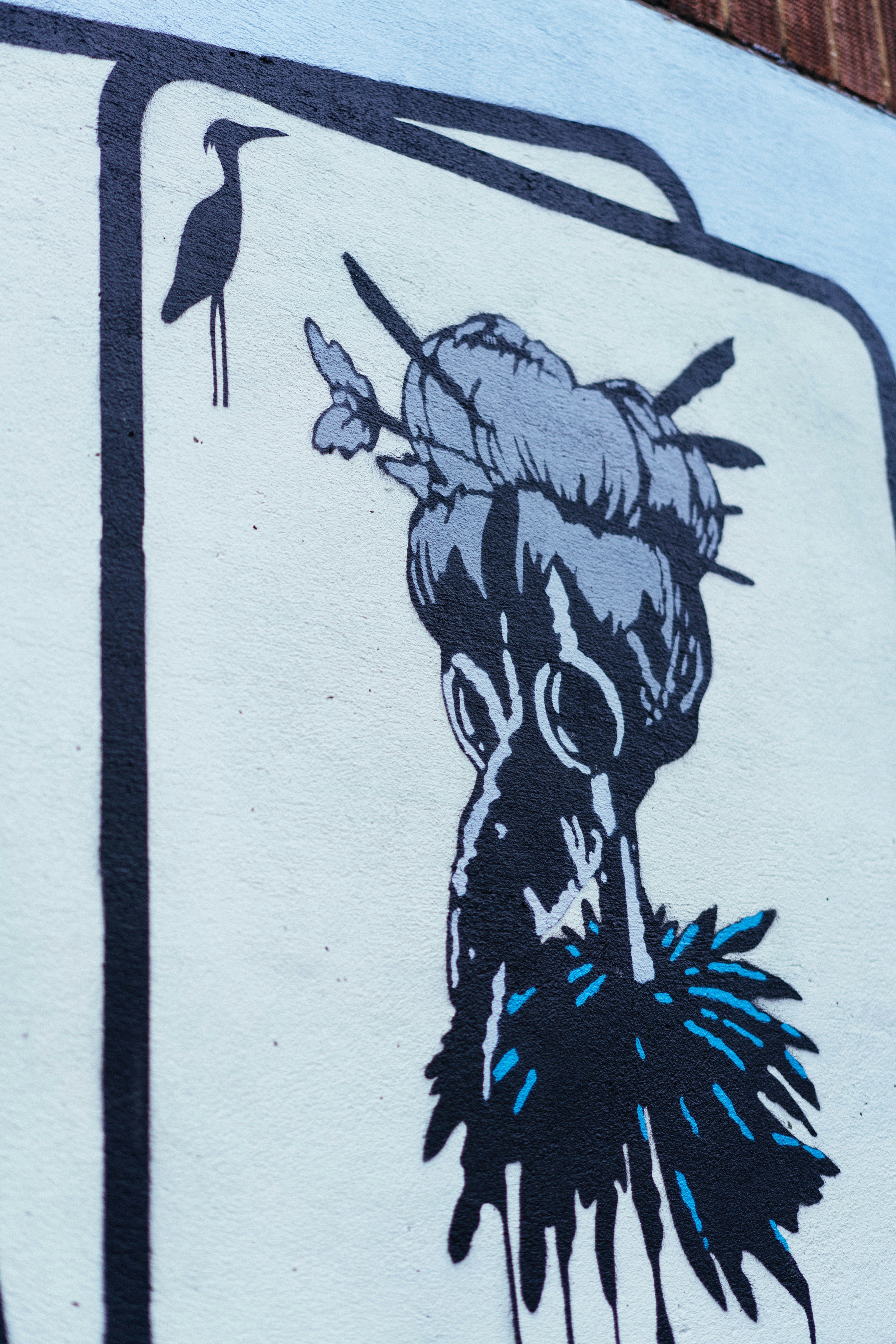 Blue-toned mural of a crowned bird on a framed panel: a stylized street art scene