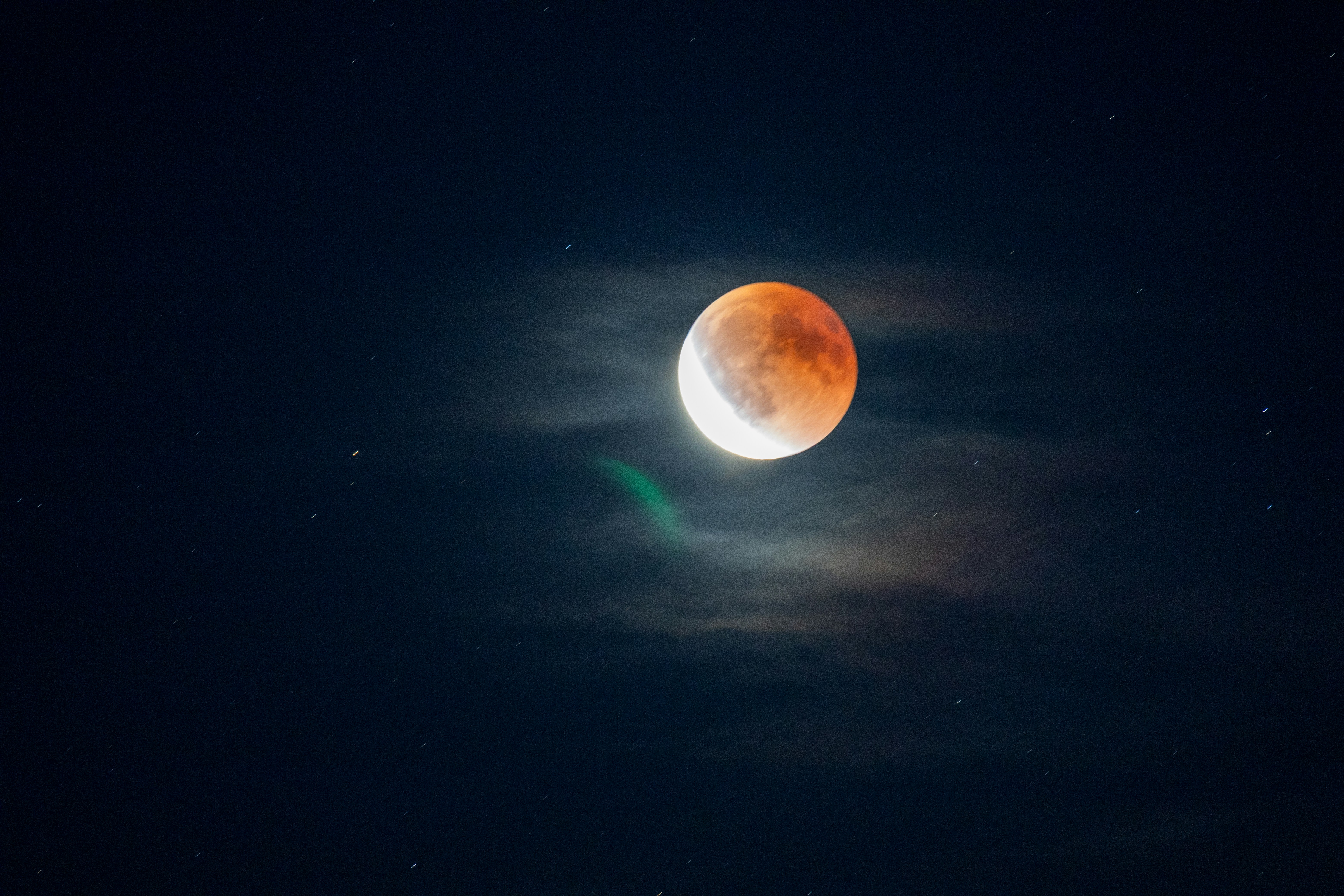 Lunar Eclipse Halo: The Red Crescent Above Quiet Nebulae