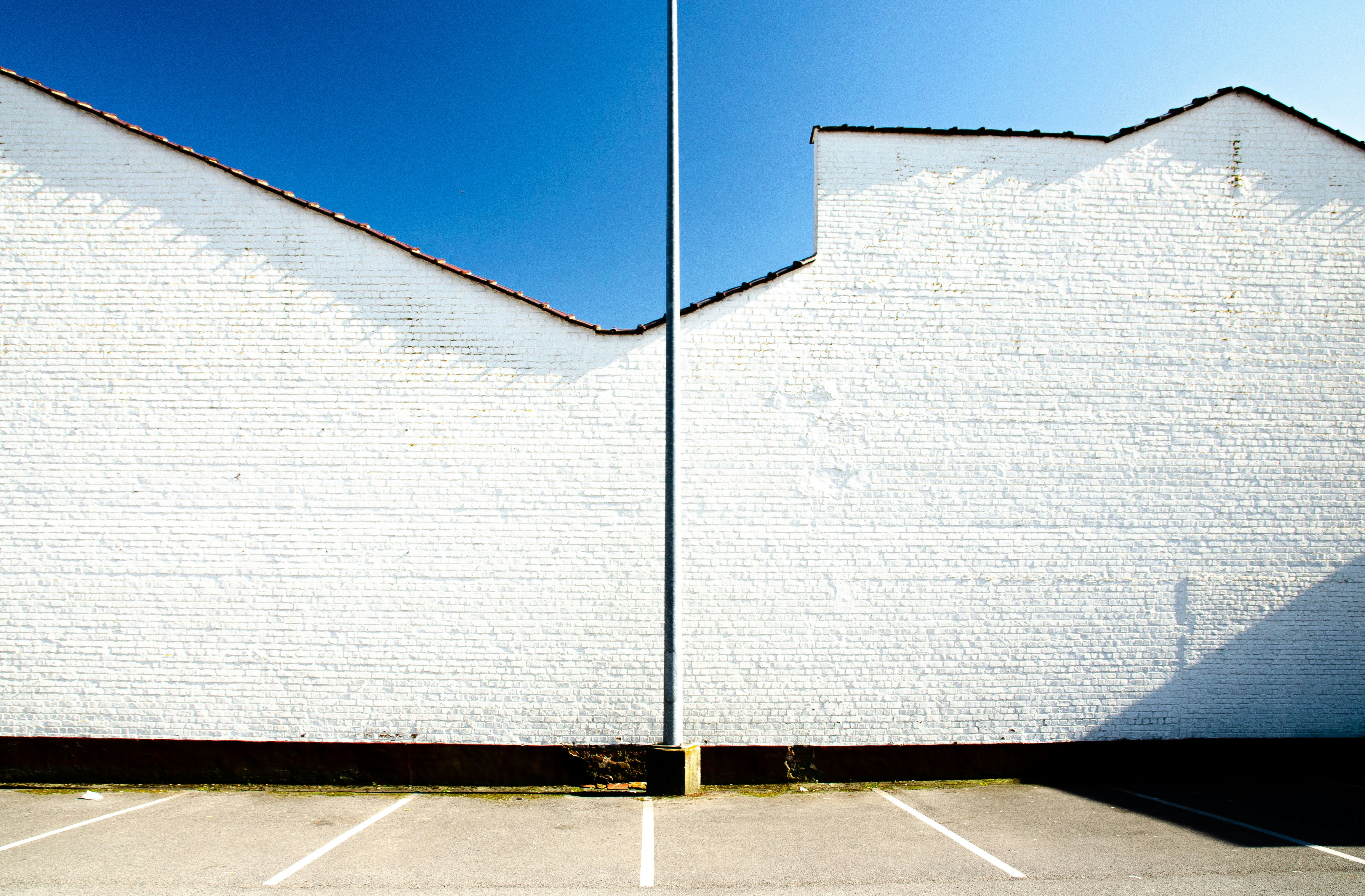 Symmetrical white wall with a lone vertical seam under a vivid blue sky