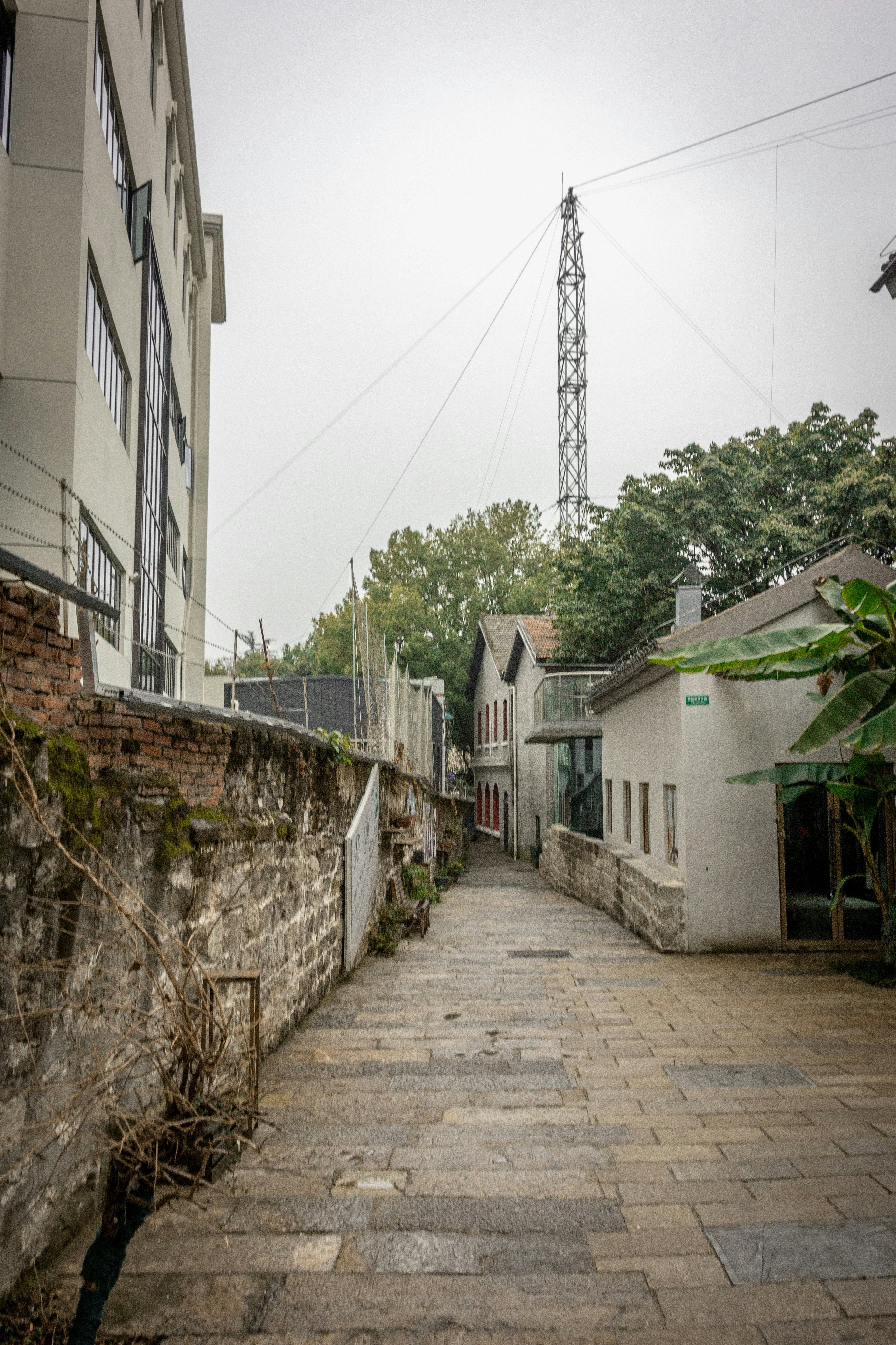 Narrow cobblestone alleyway between buildings with tall tower.