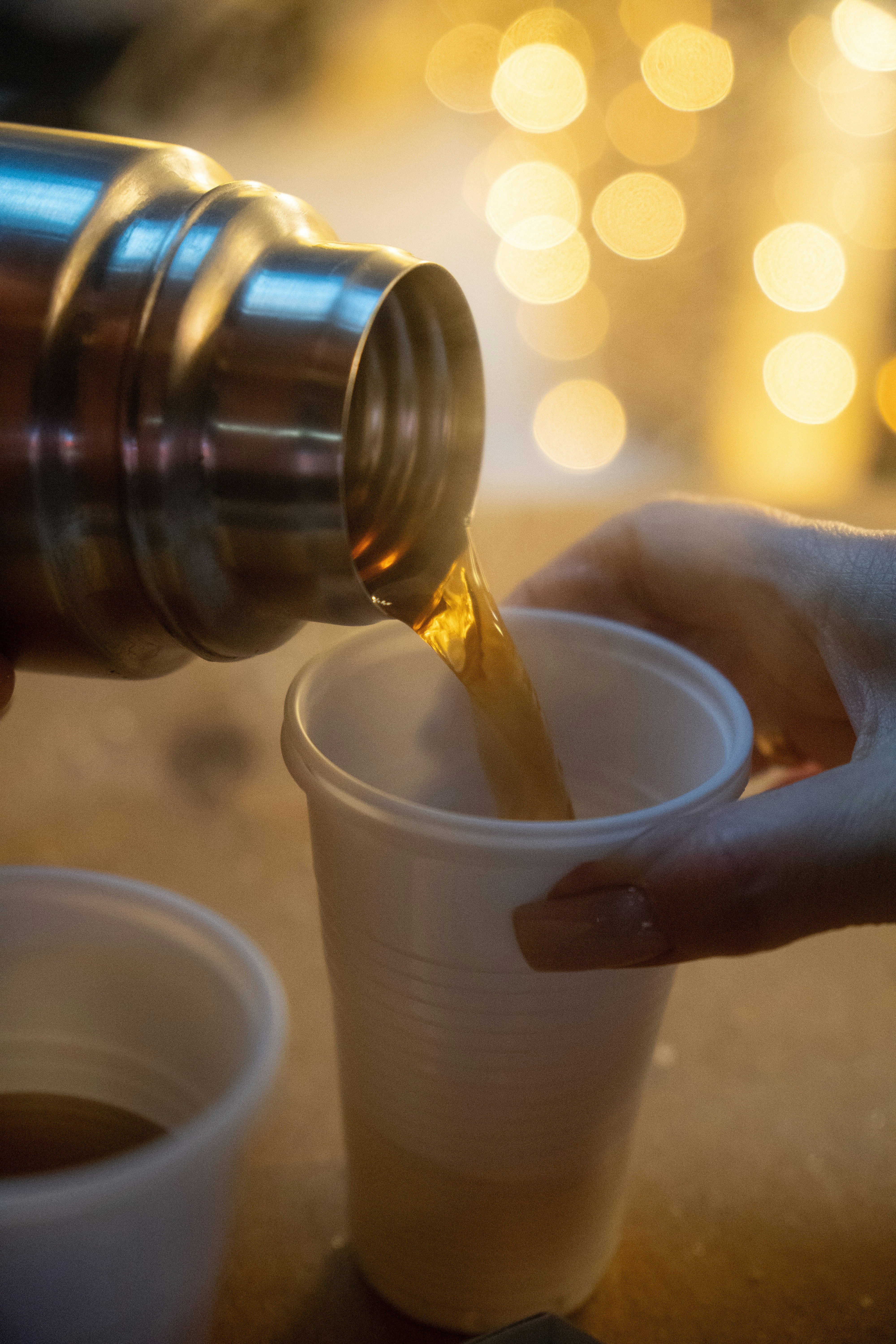Warm Spill: Pouring Coffee into a White Cup Under Soft Evening Lights