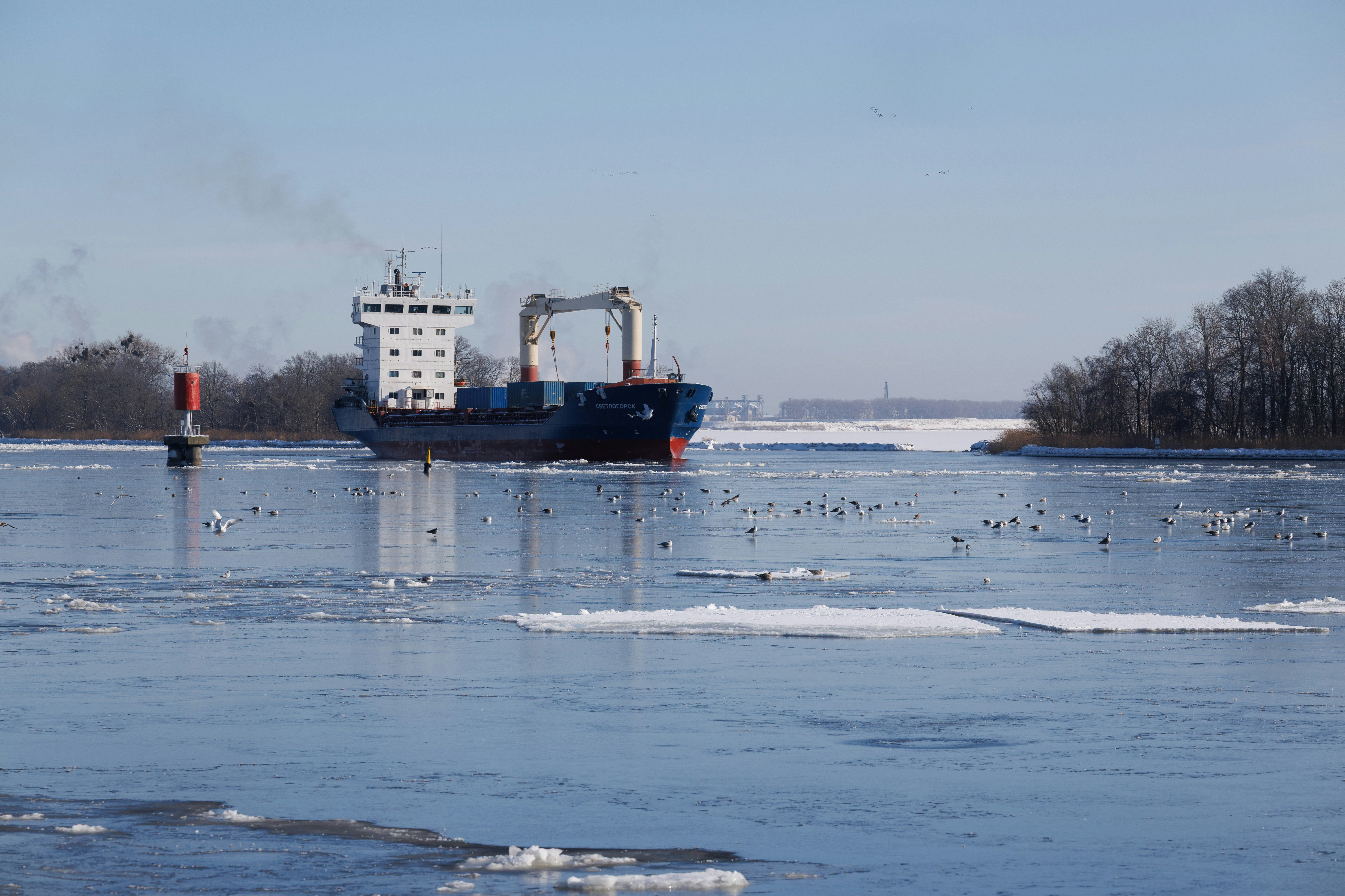 Icebound Freight: A Blue Hull Carries Through an Autumnal Fjord