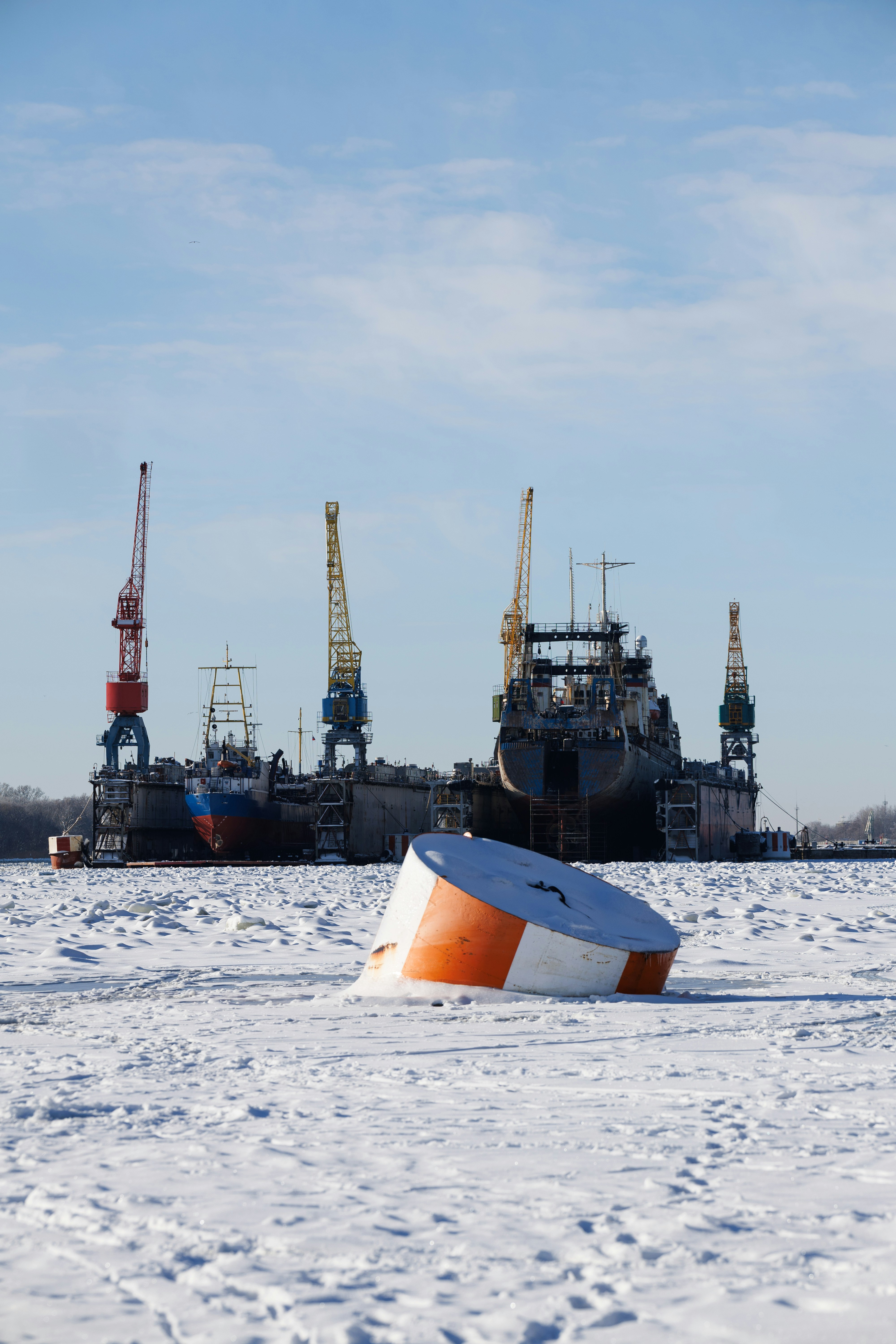 Docked Giants in Winter: Cranes and a Slanted Buoy