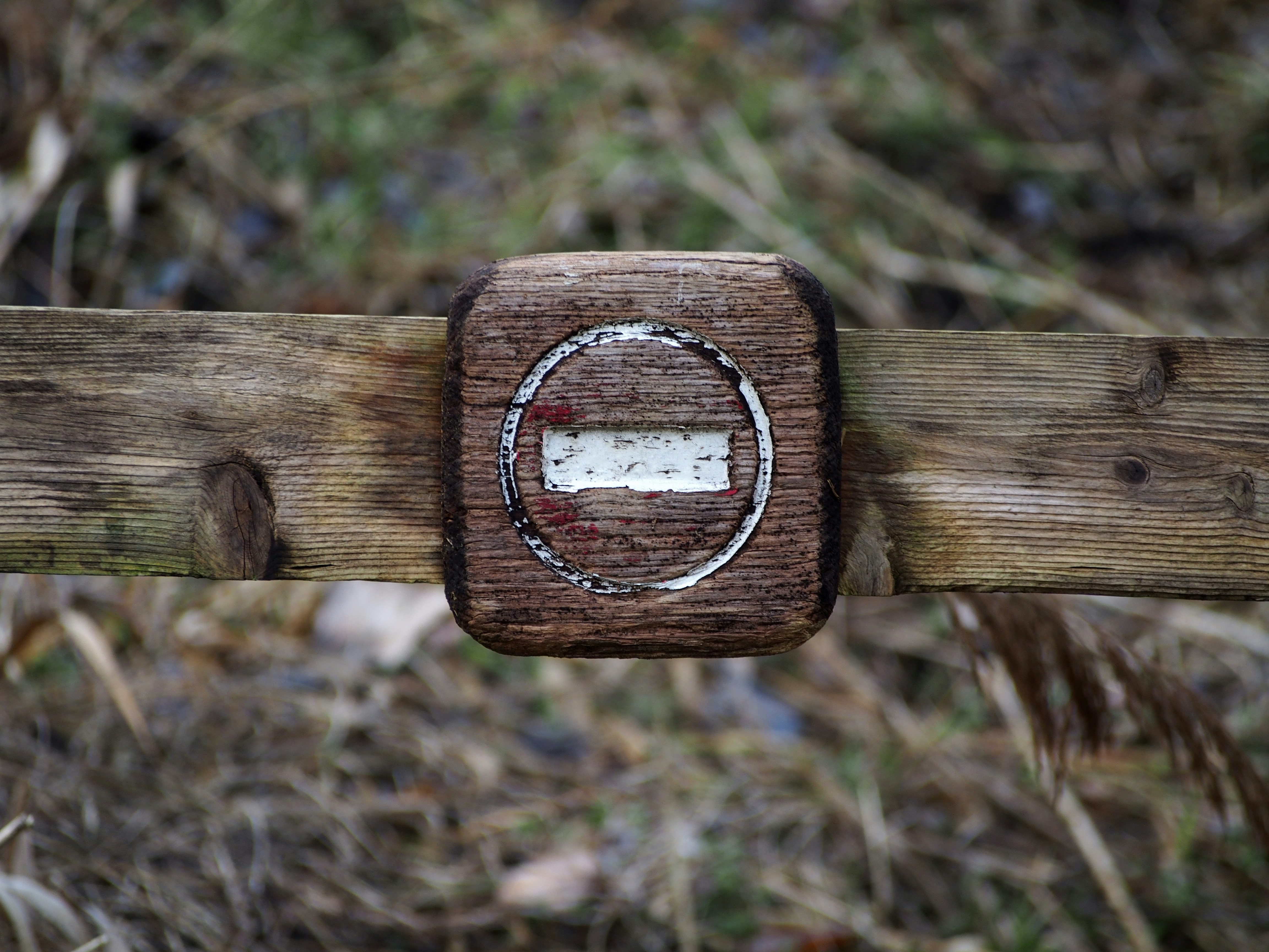 Weathered post with faded circular emblem centered on a rustic wooden beam