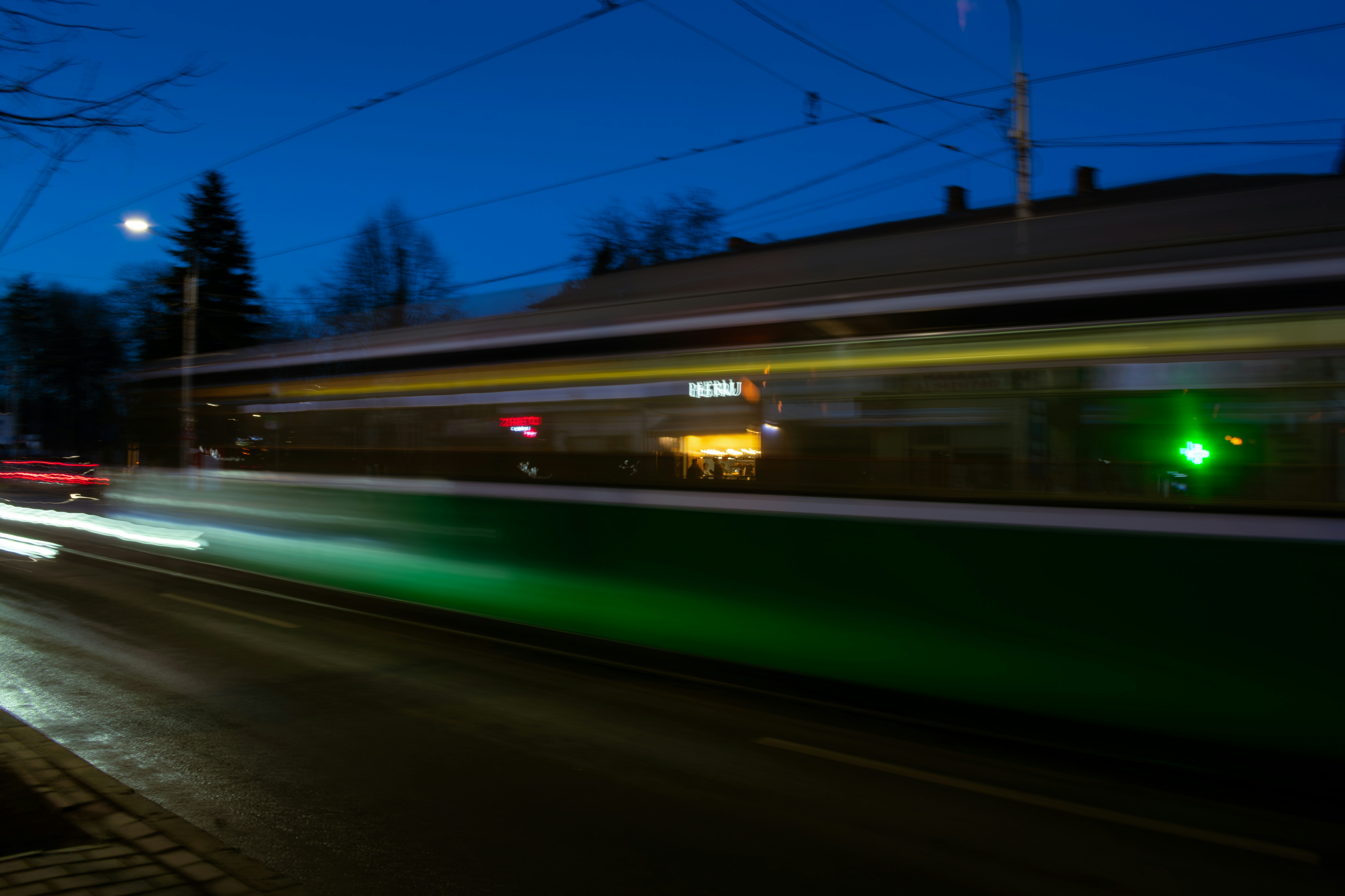 Night Tram in Motion: Neon Streaks Across a Shadowed Street
