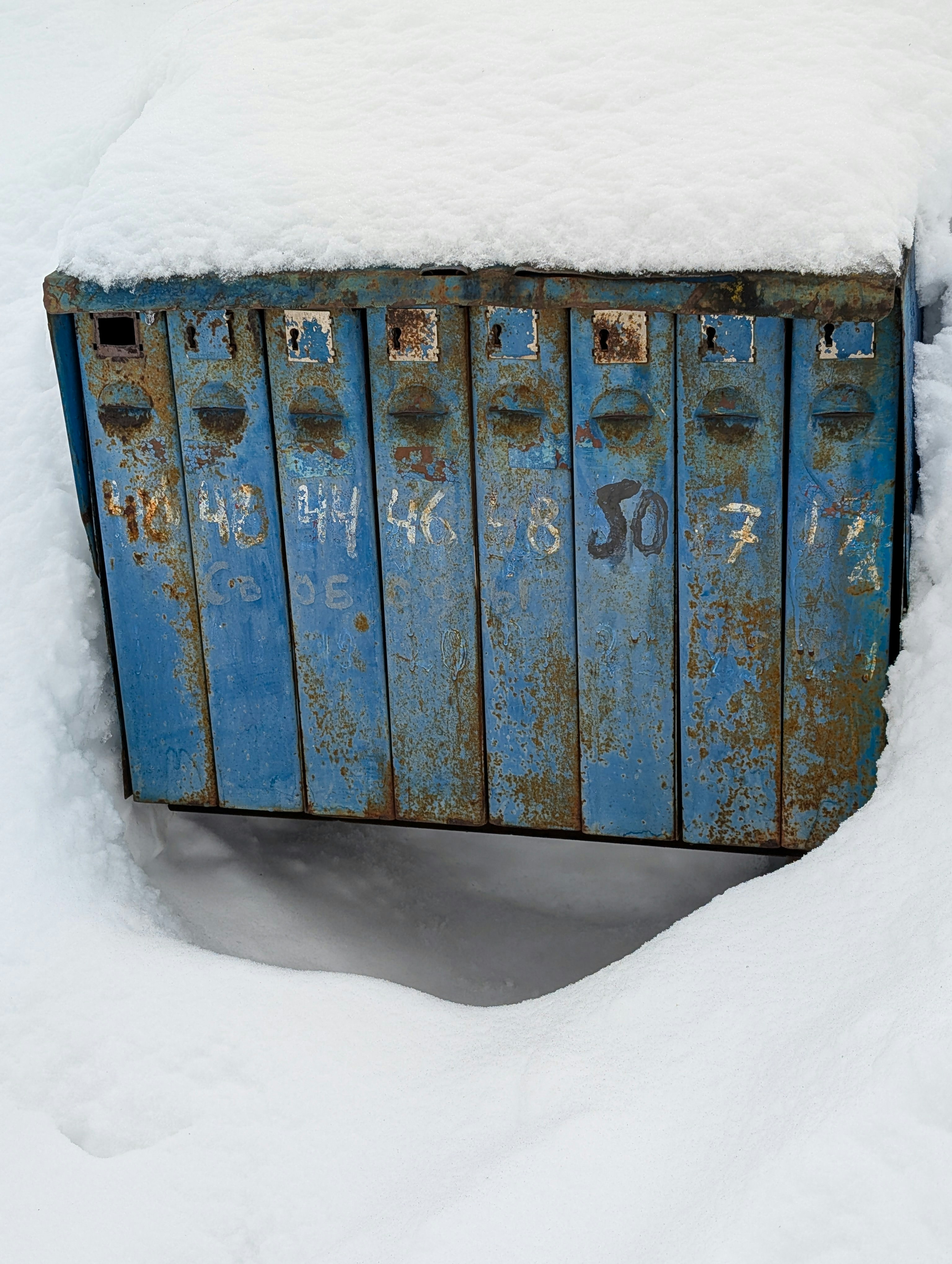 A blue postbox covered in snow in winter.