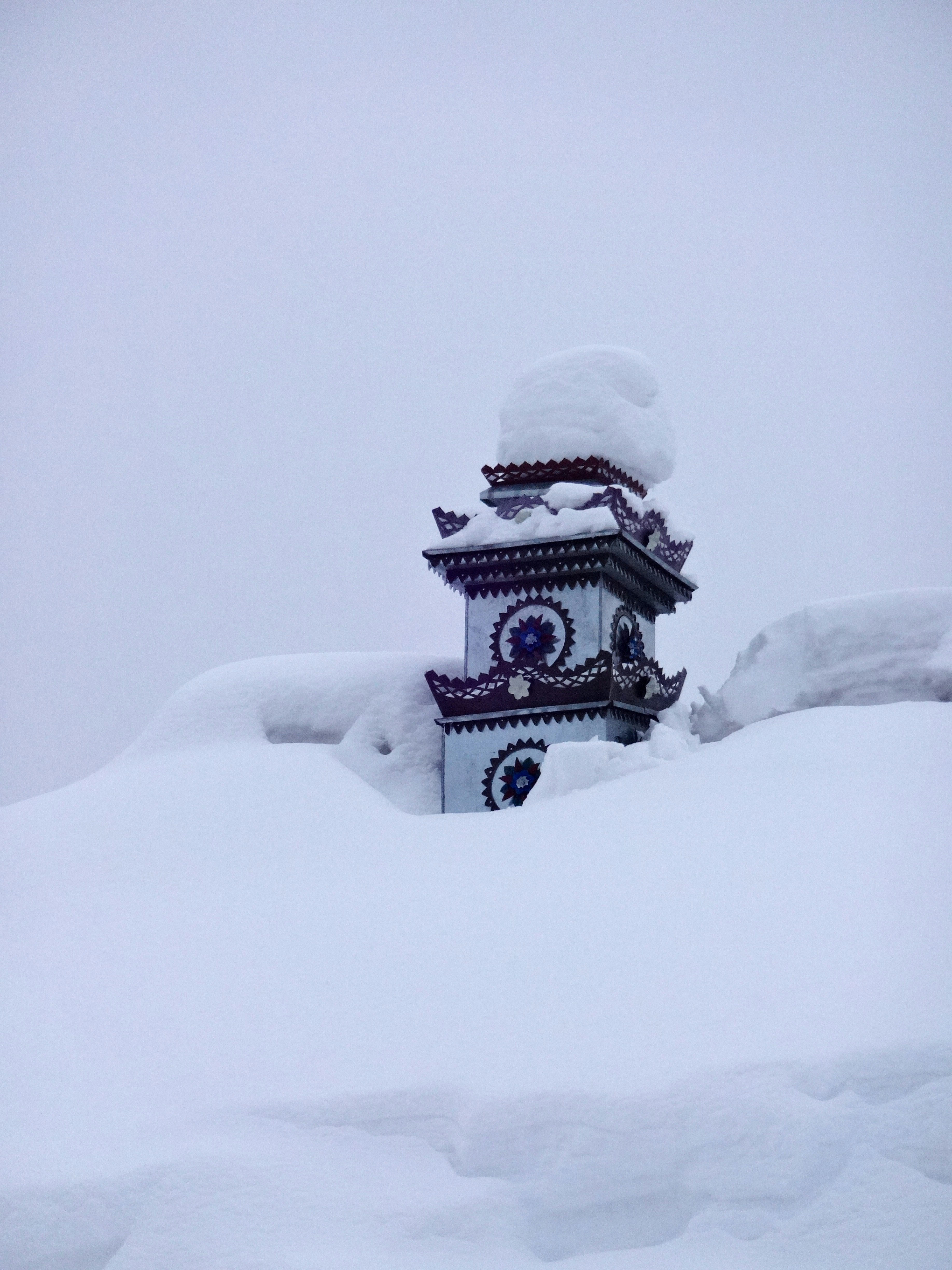 A stove pipe covered by heavy snow in winter.