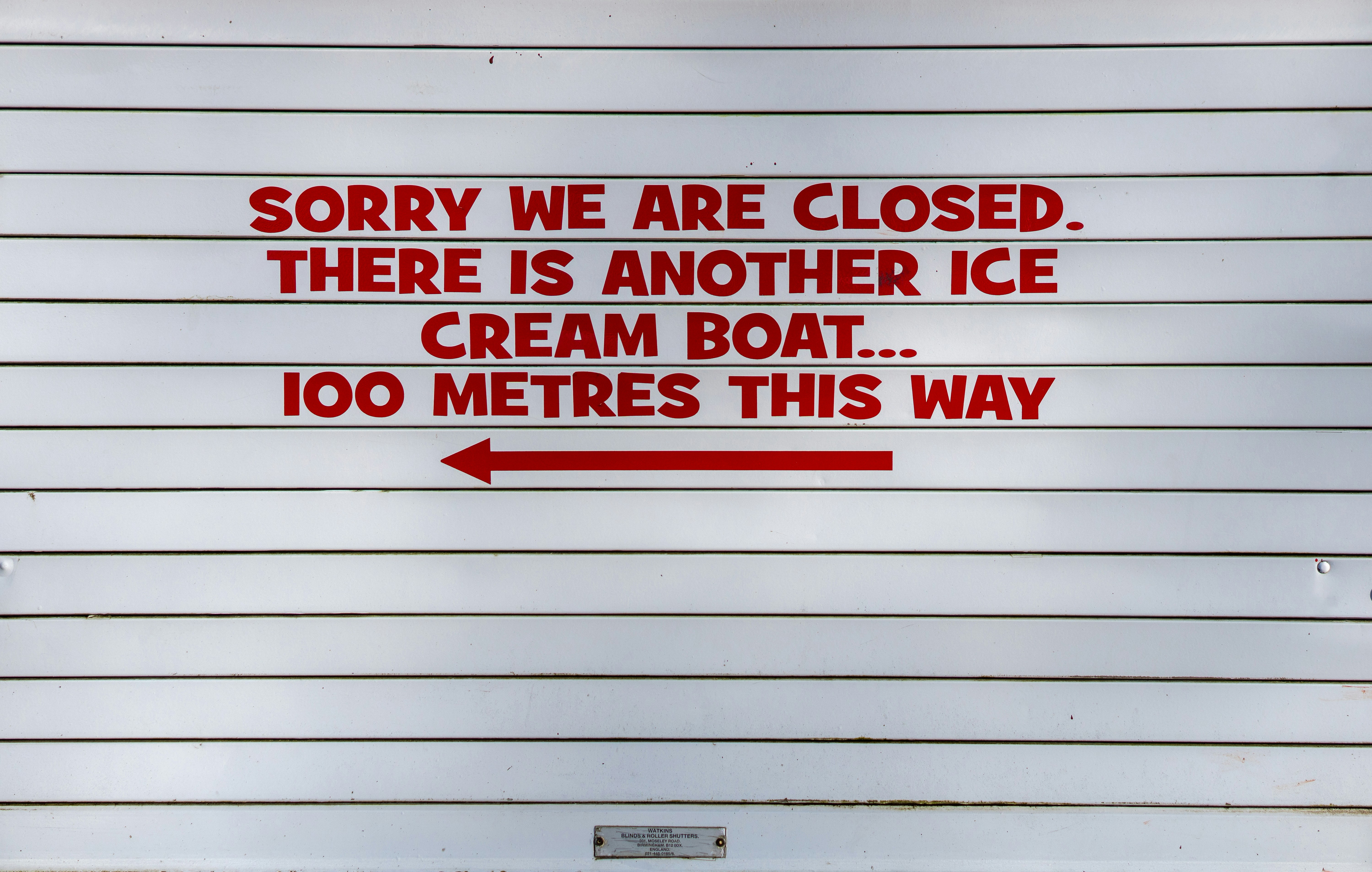 Red Text Signpoint: A Closed Ice Cream Boat Sign on White Slat Wall