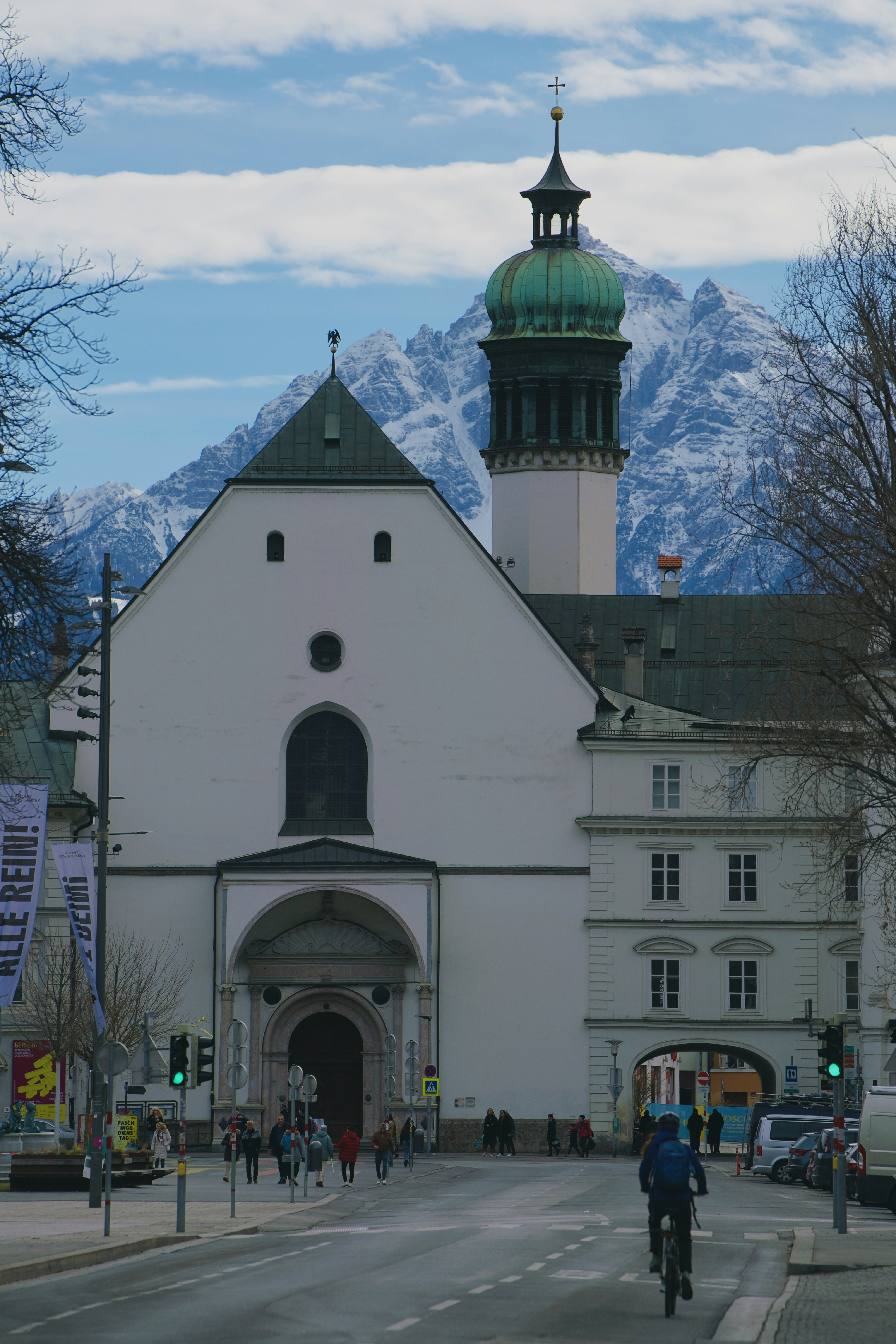 Snow-capped Alps reveal a Baroque church under a green-domed tower