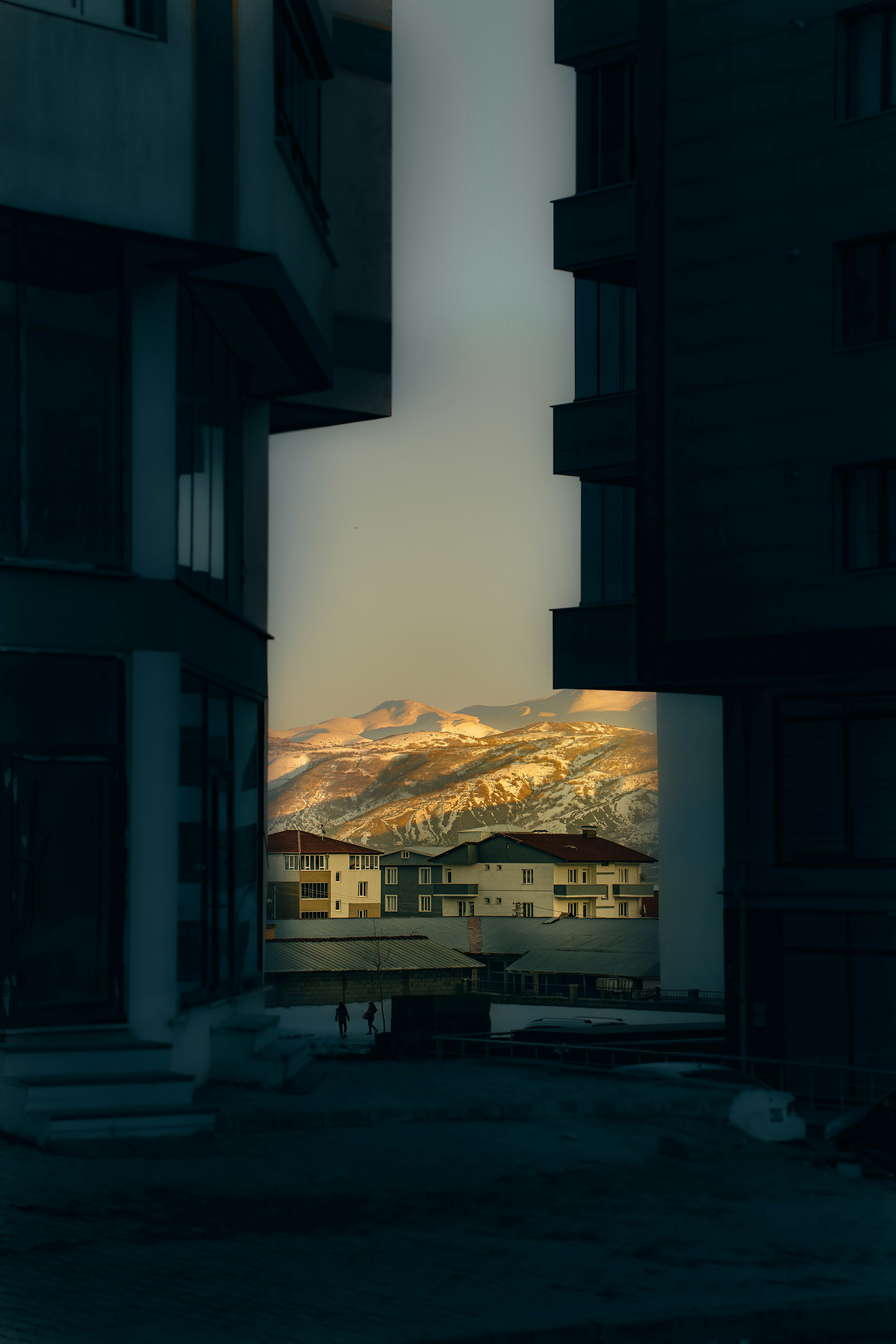 Gap in the City: Snow-Capped Summit Framed by Narrow Street
