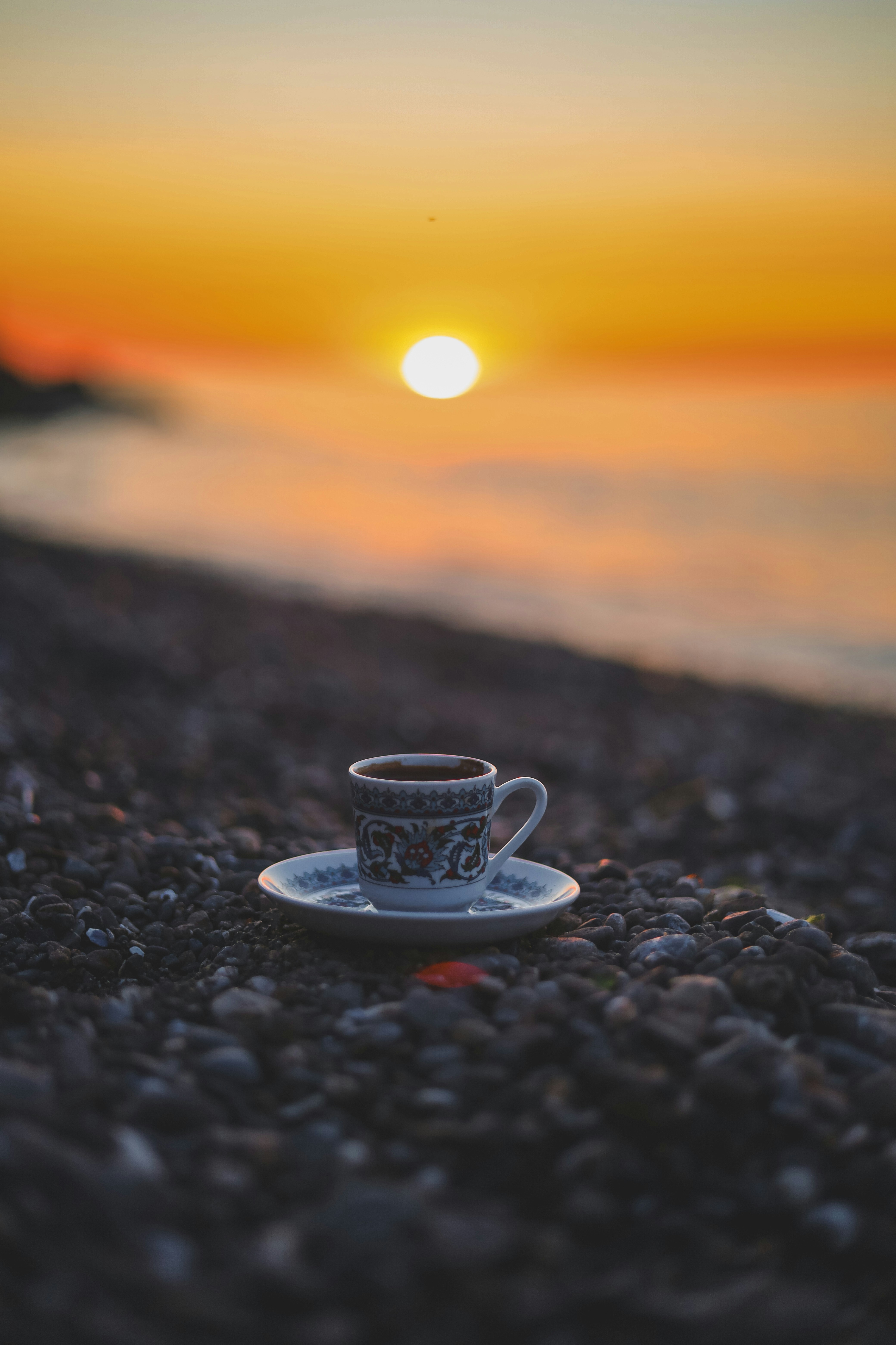 Sunset Reverie with a Ceramic Cup Resting on Pebbles