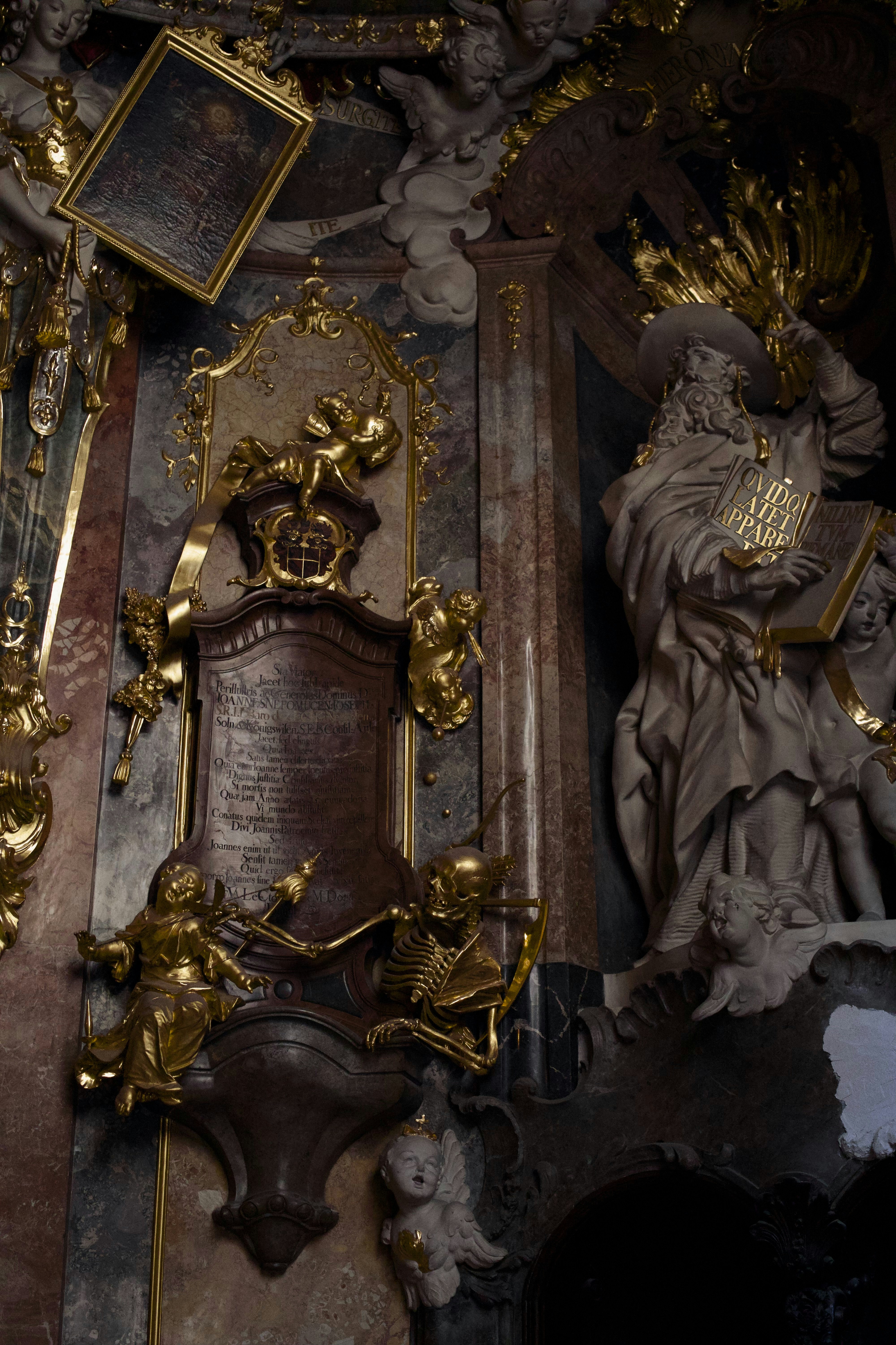 Baroque Sanctuary: Gold Cherubs and Carved Memorial in Dimly Lit Chapel