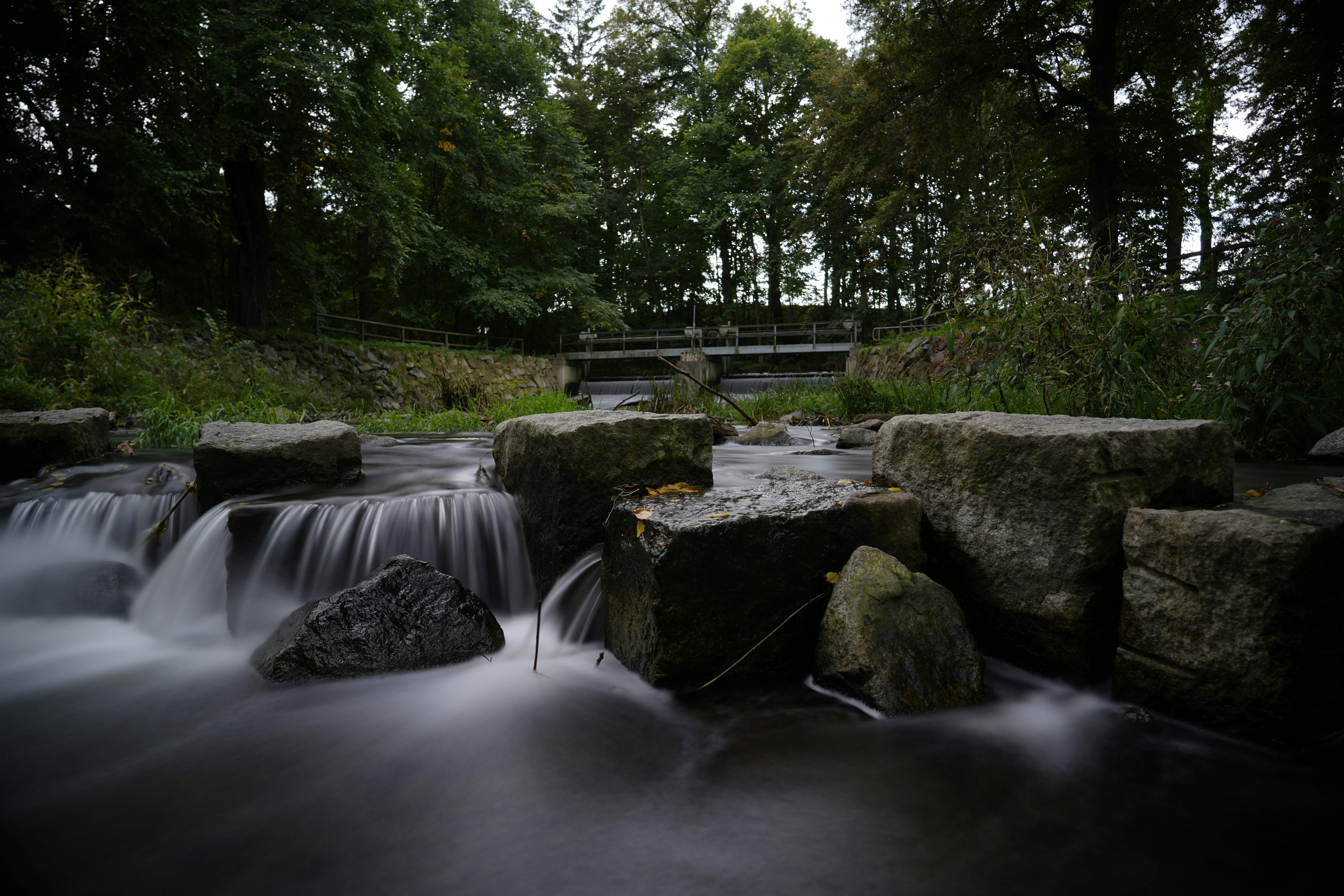 Rushing Stream over Stepped Granite under a Shaded Bridge