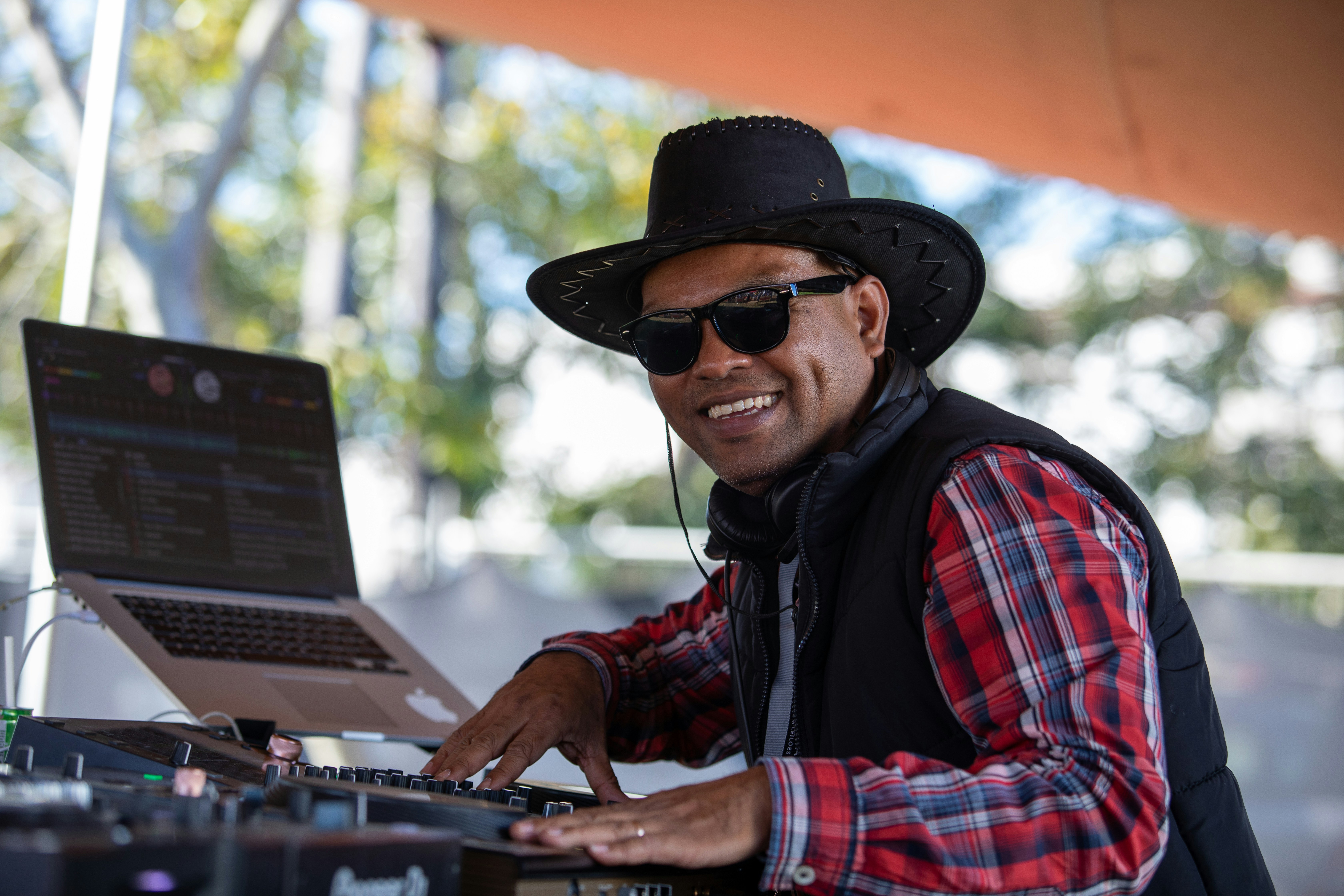 DJ on Deck: A DJ in a sunlit outdoor setup with laptop and mixer
