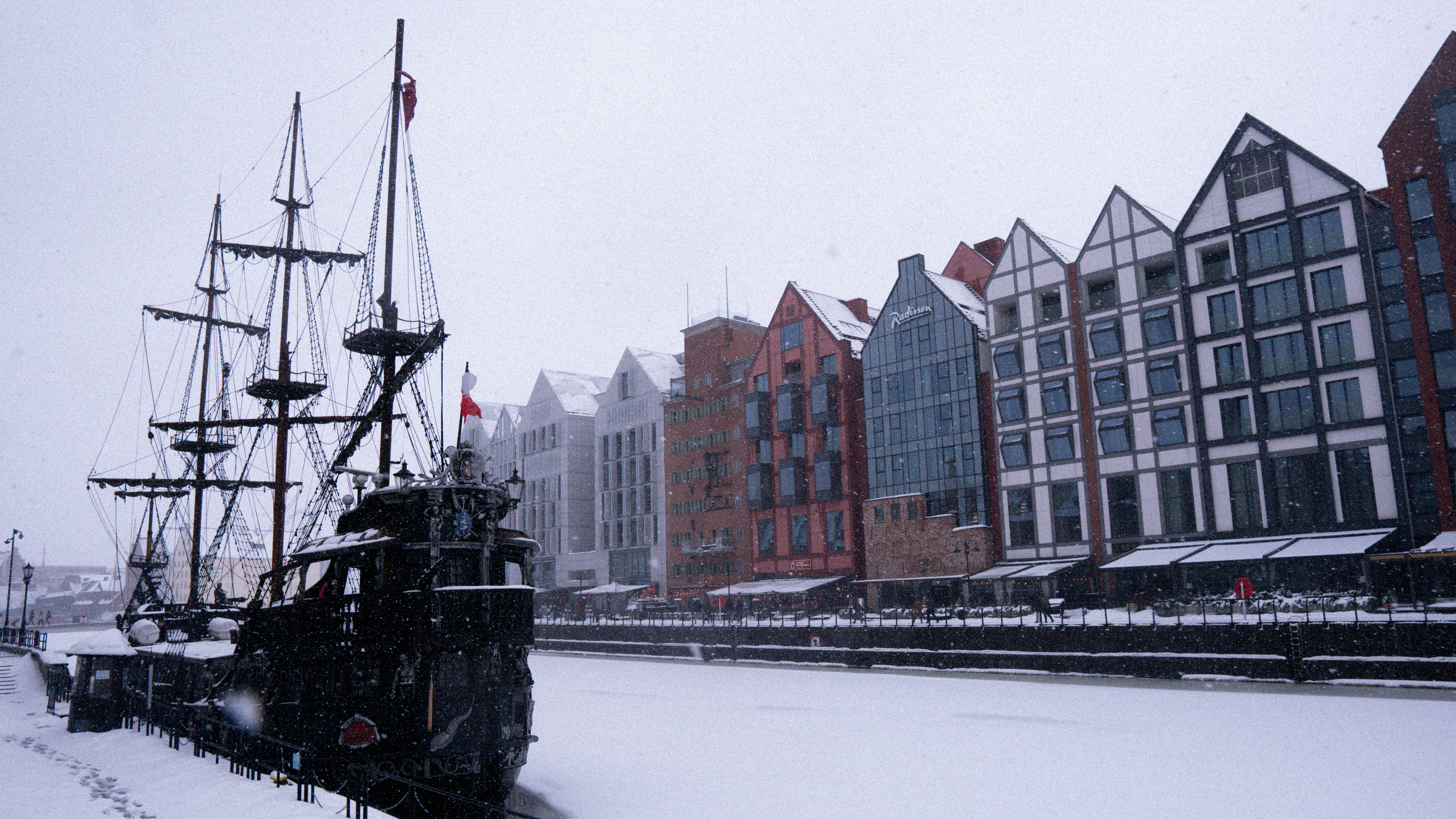 Snowbound Hull: A Historic Vessel Docked Along a Frosted Canal
