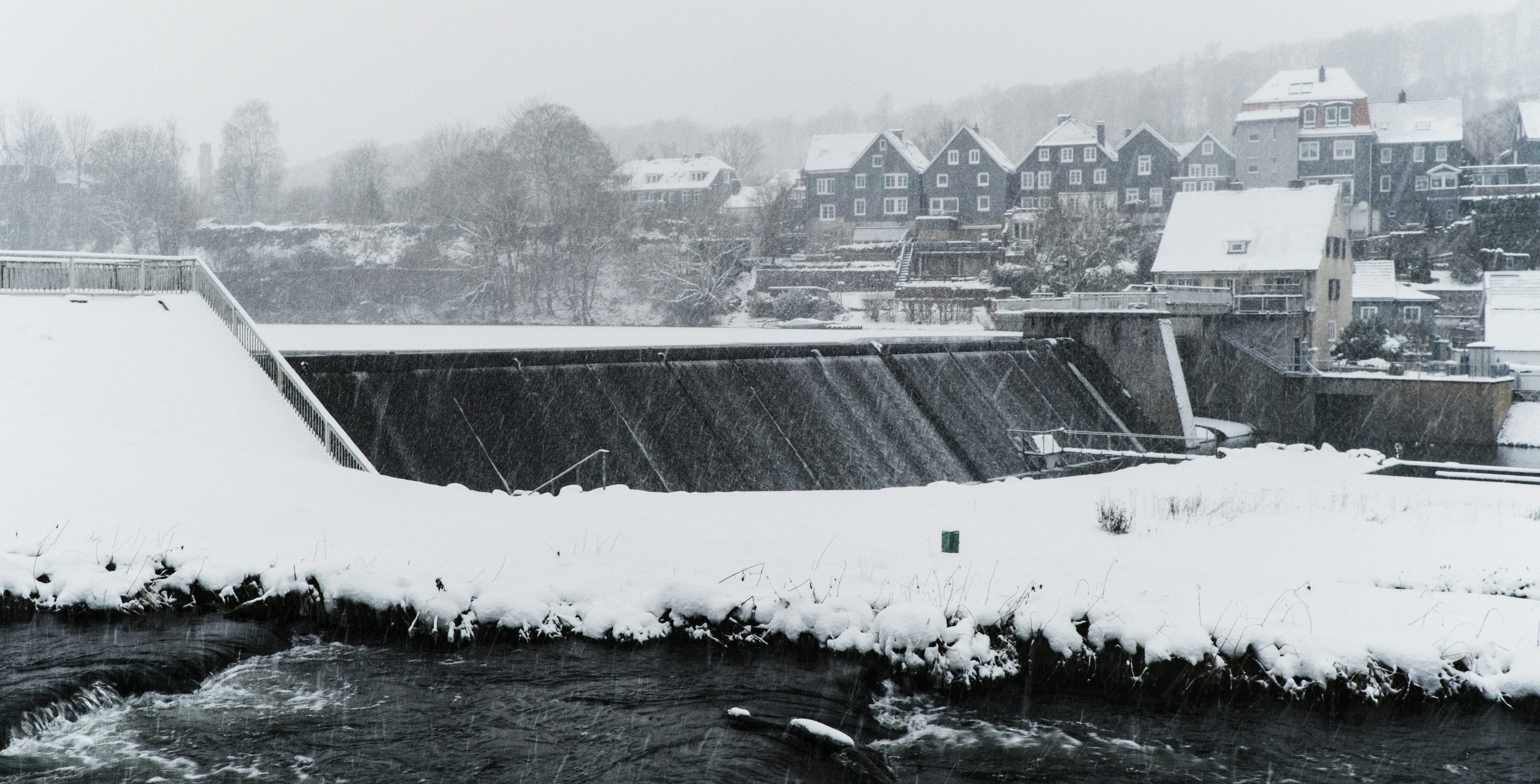 Winter Weir: Snow-Covered Spillway Framed by Quiet Village