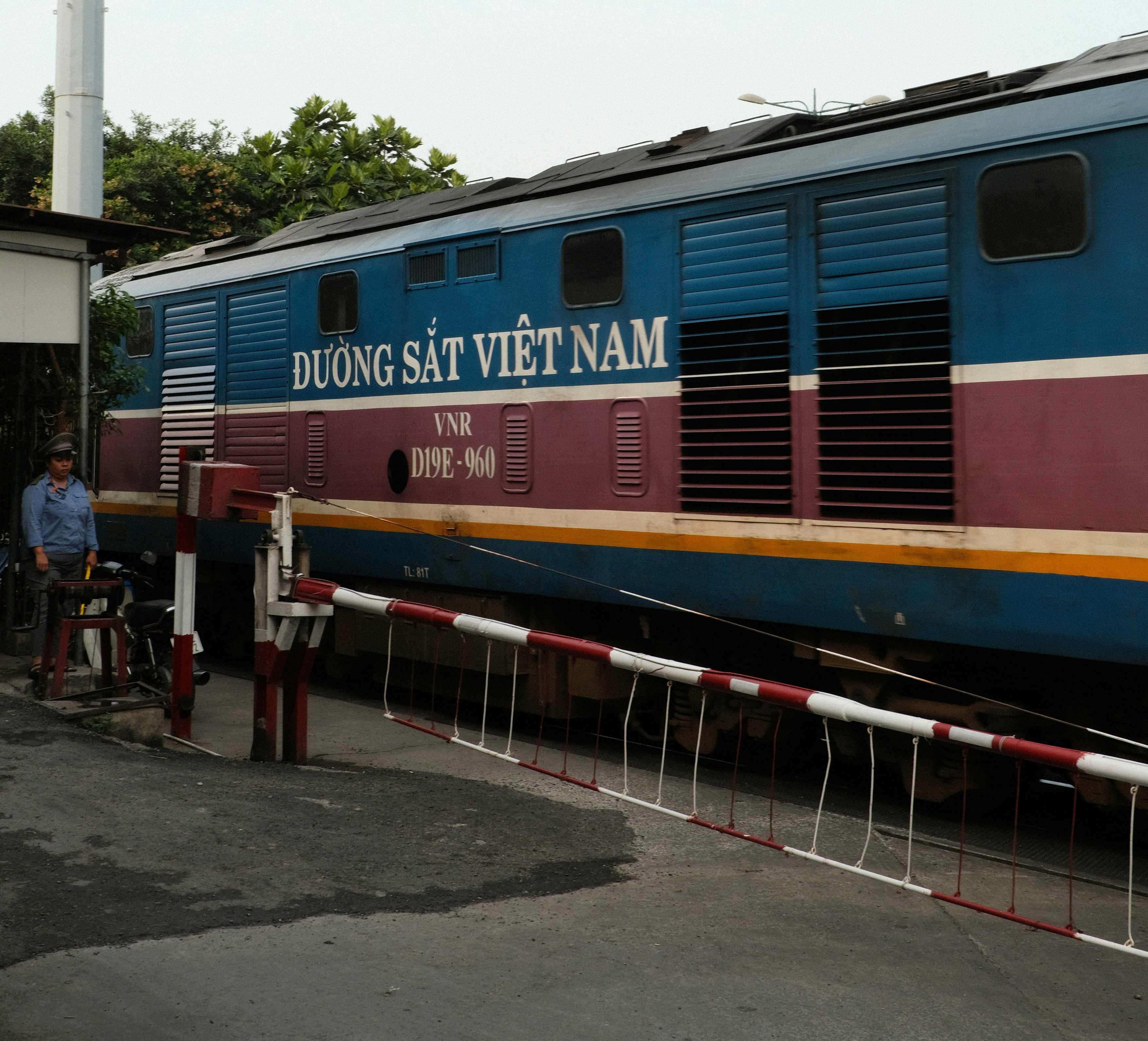 Blue locomotive at a rural Vietnamese crossing