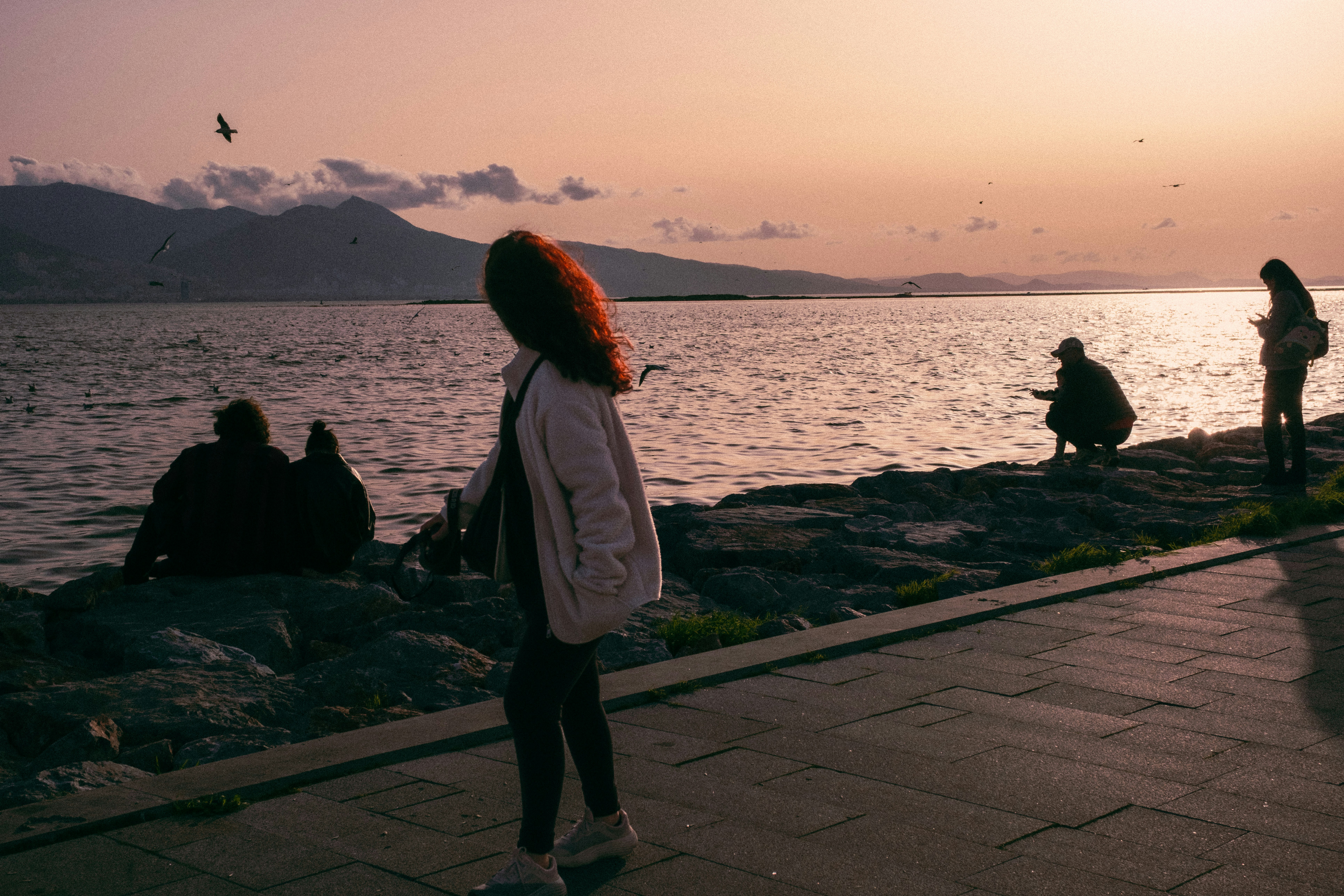 Silhouette on the Promenade: Sunset over the Quiet Cove