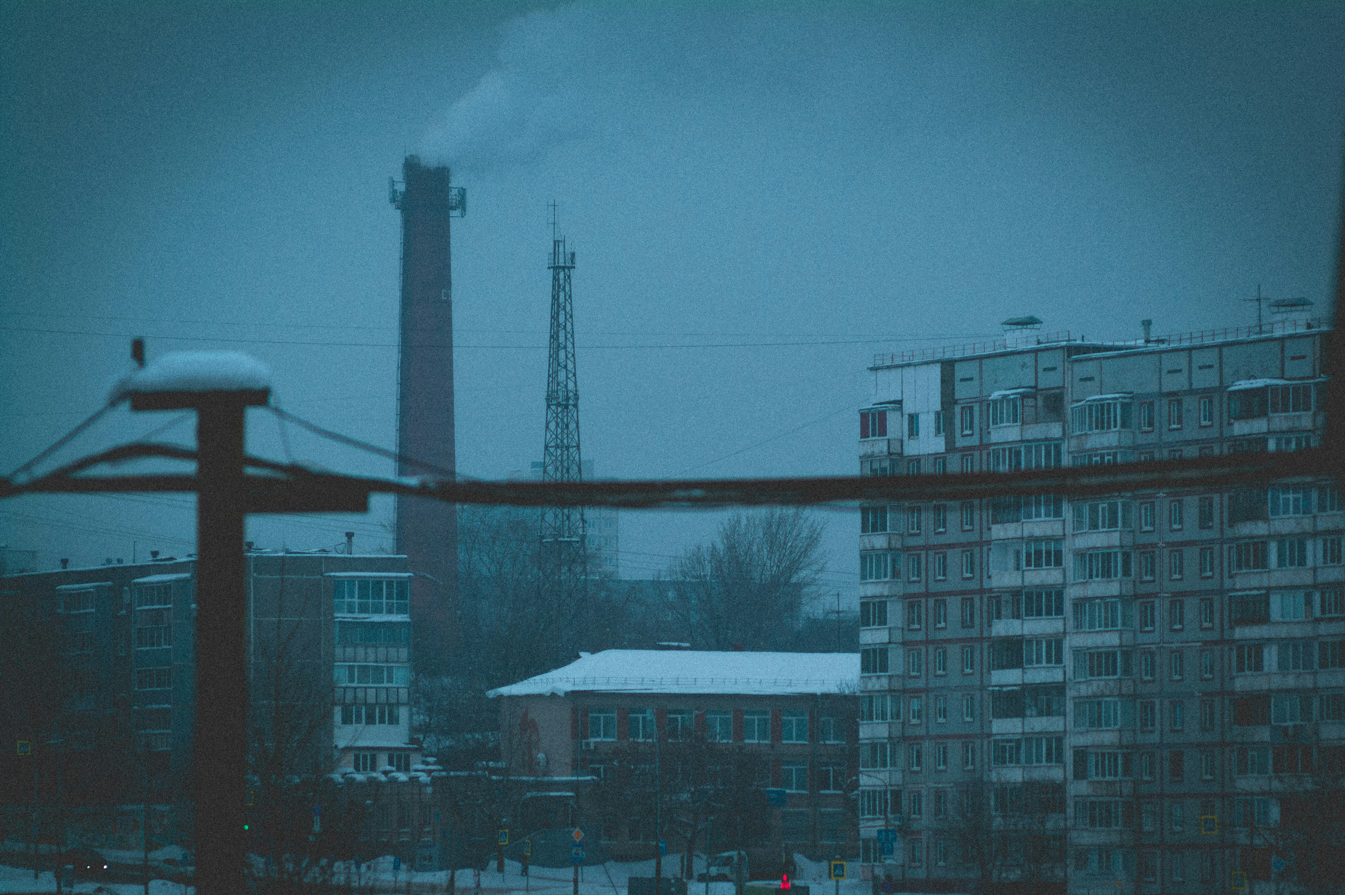 Industrial cityscape with smoking chimney and apartment buildings.