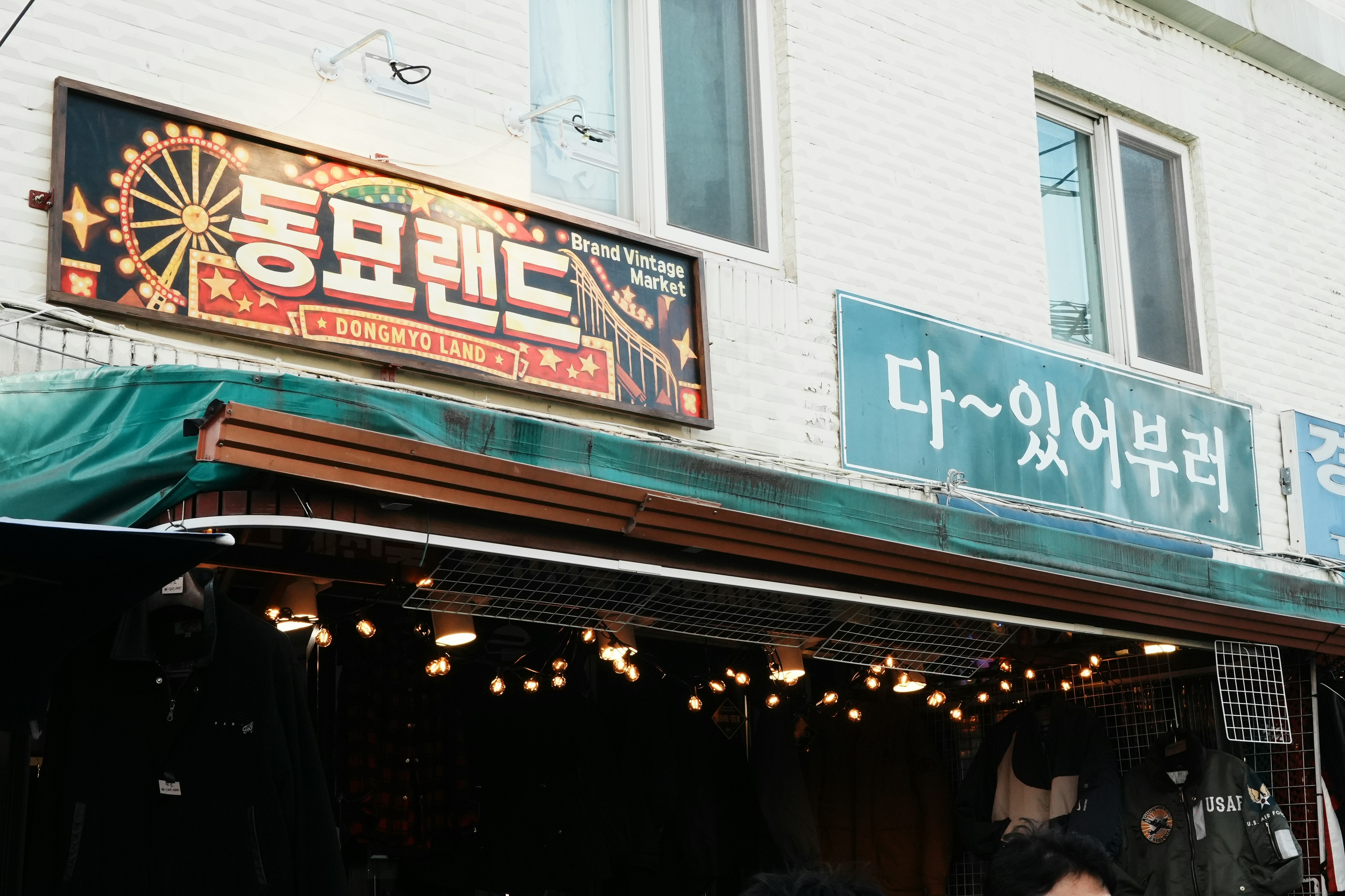 Duo of storefront signs: neon dreams above a market’s bustling facade