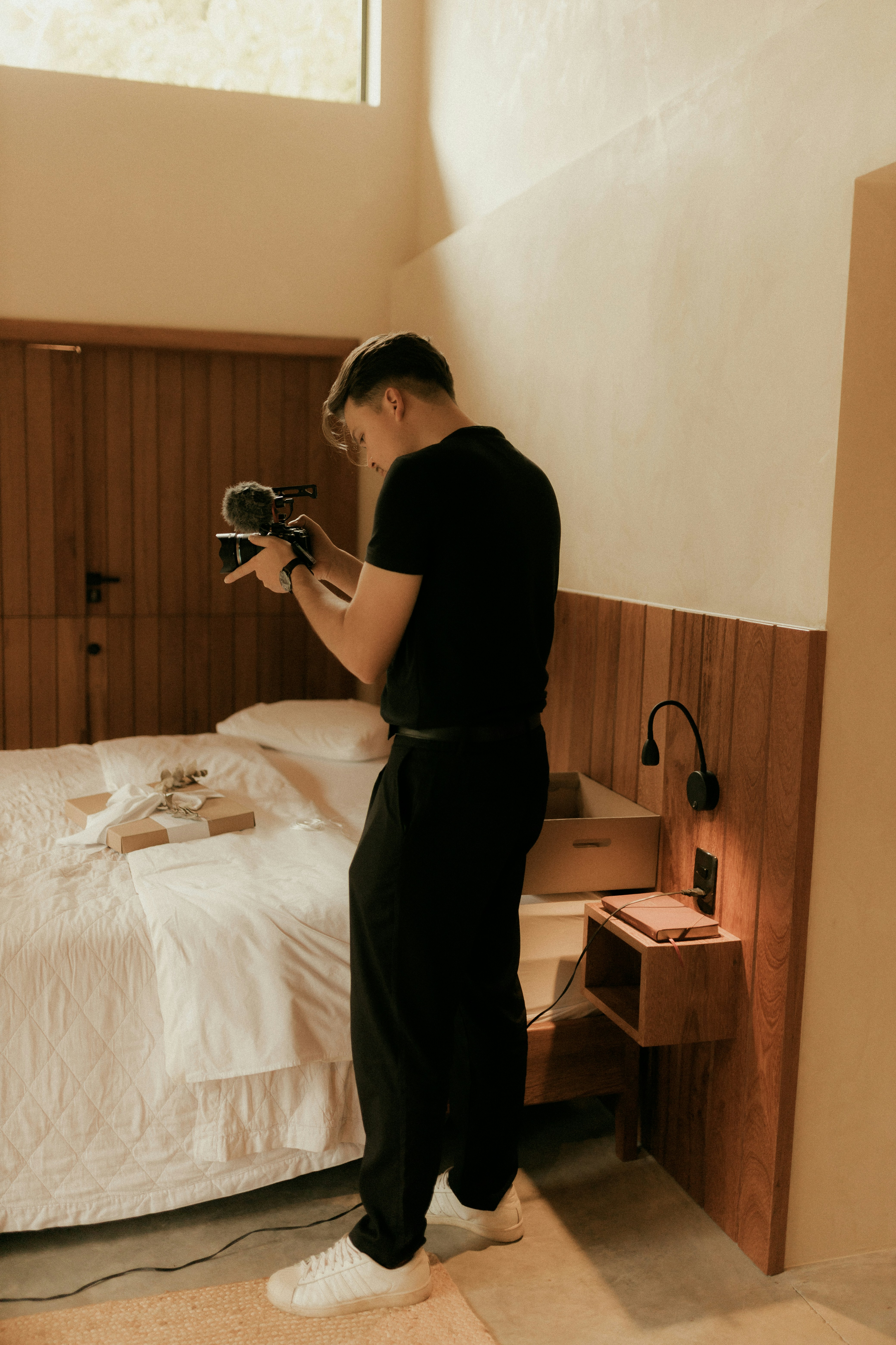 Courting Light: A filmmaker adjusts gear in a softly lit bedroom studio