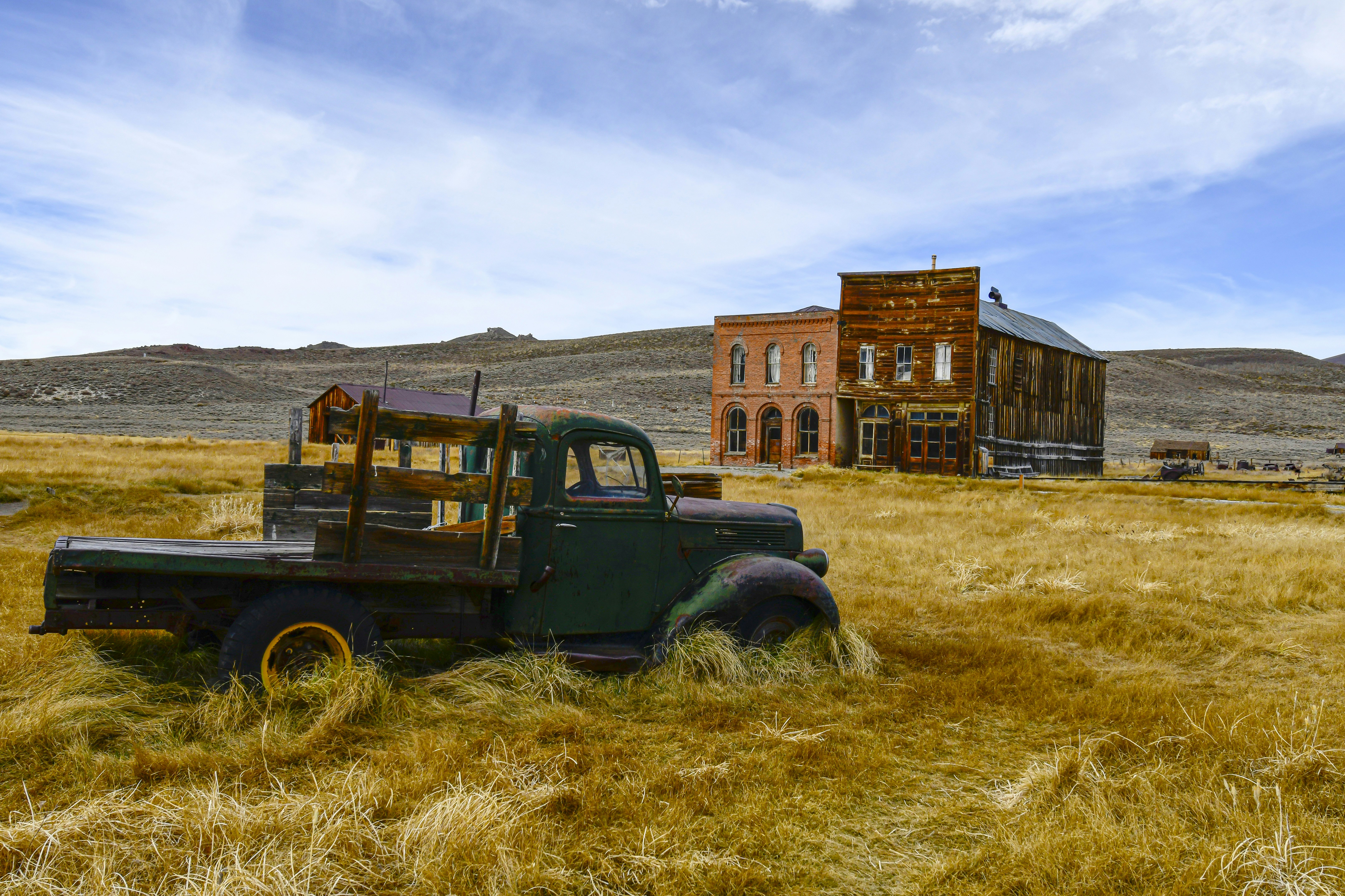Deserted Freight: An Abandoned Truck and Weathered Brick Mill Stand Guard over Golden Grass