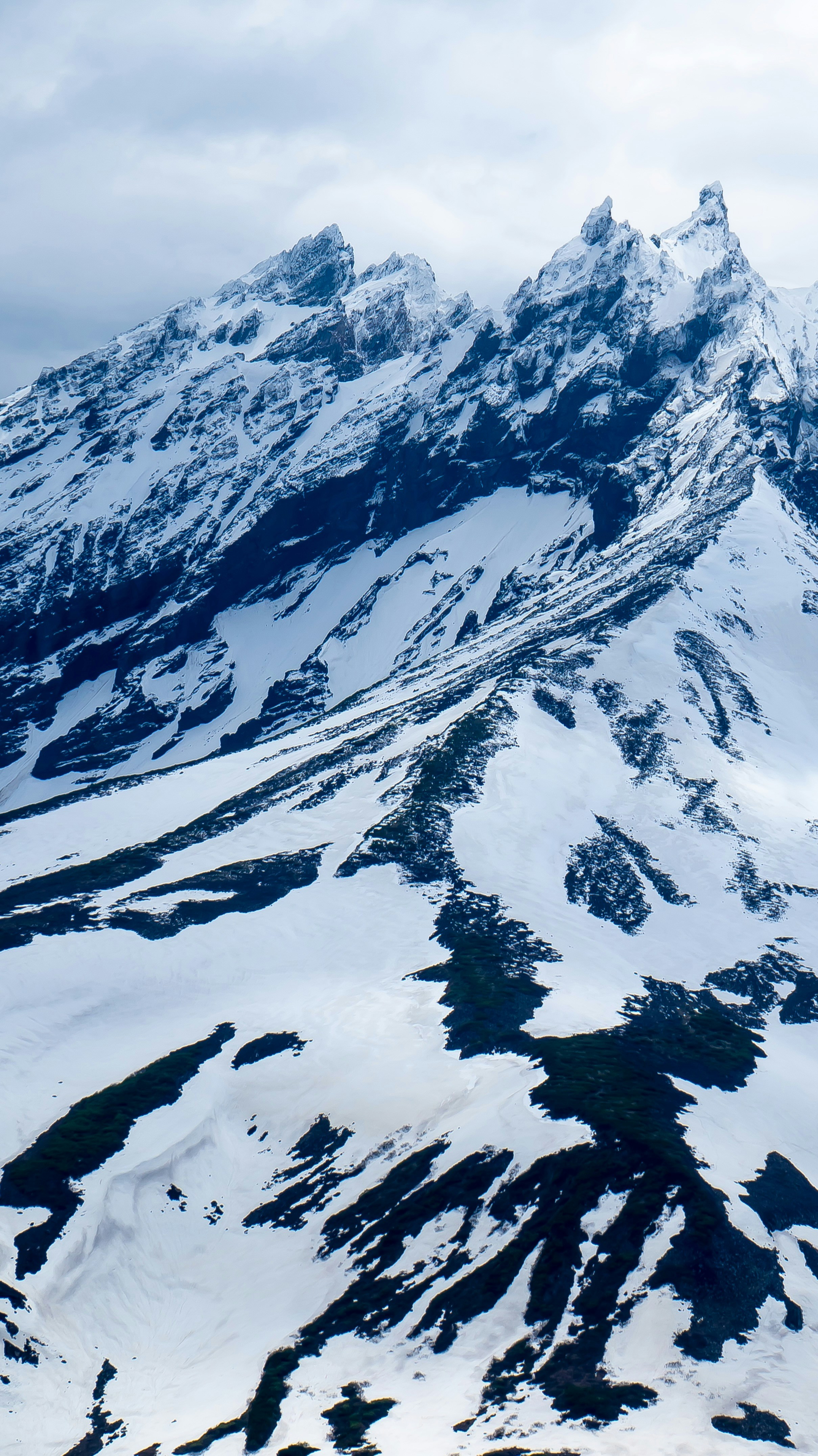 Icy Spine: Snow-Crowned Peaks Cutting Through Pale Sky