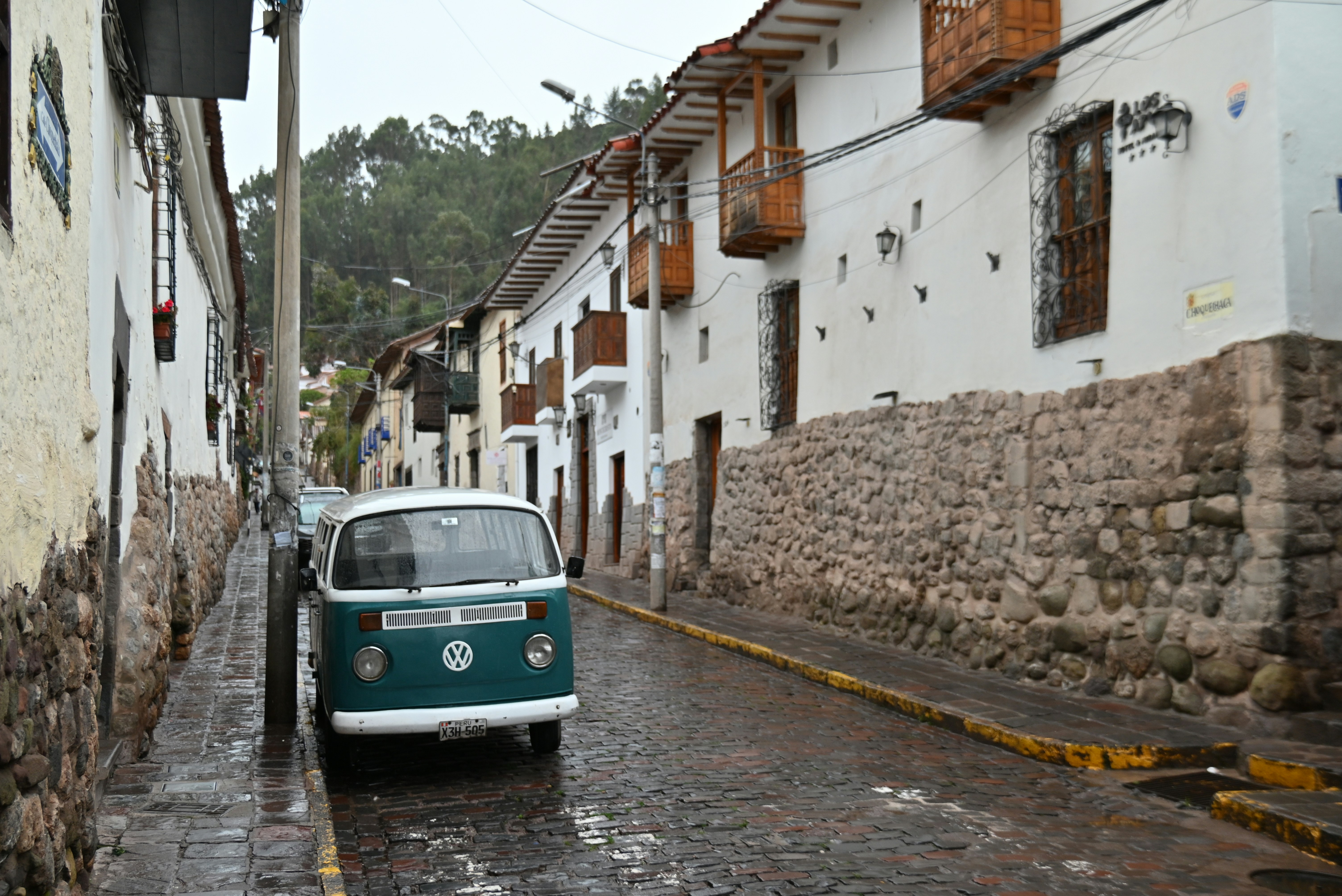 A teal vintage van Halts a Narrow Cobblestone Street
