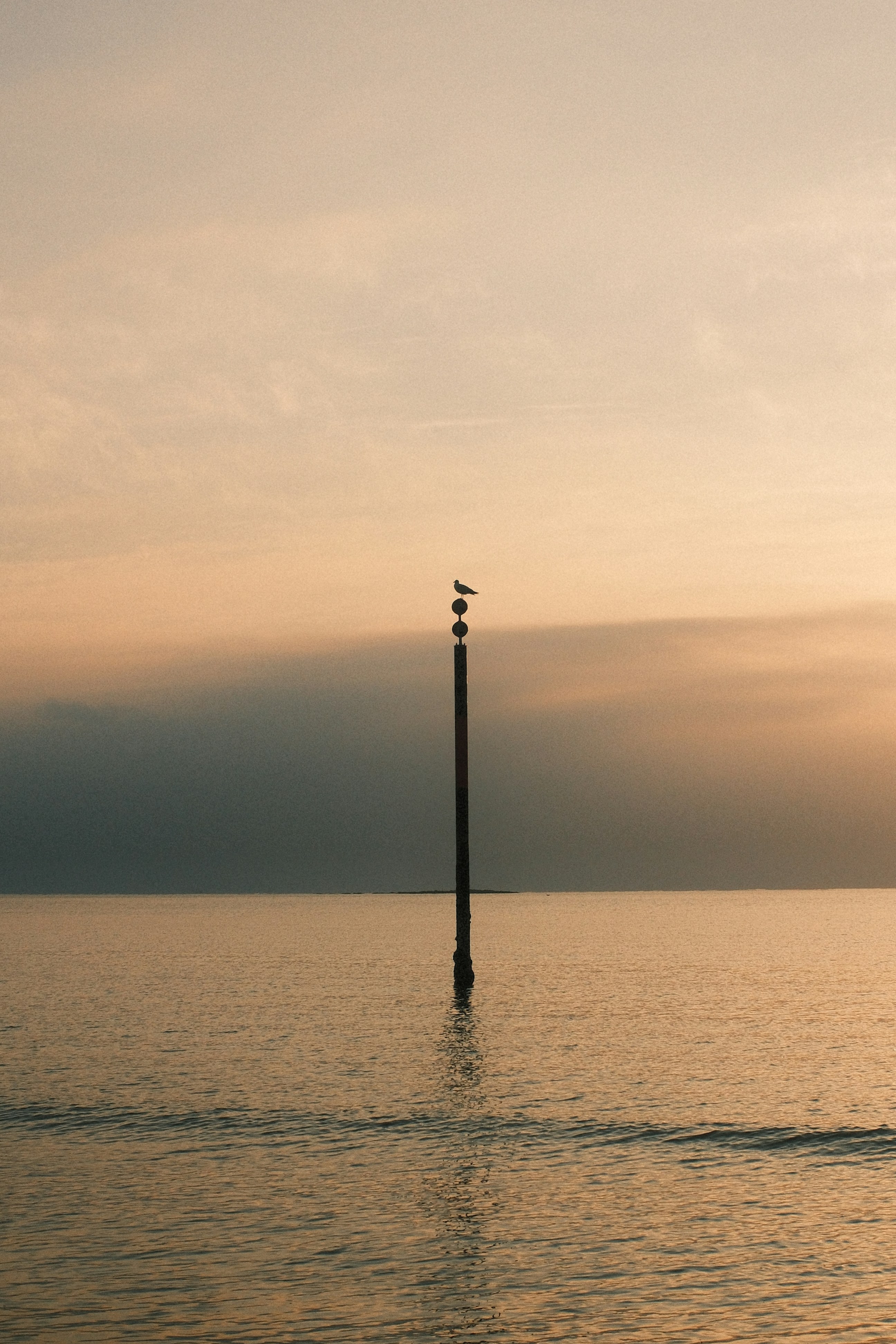 Silhouette Beacon at Dusk: A Lone Marker Against a Calm Sea