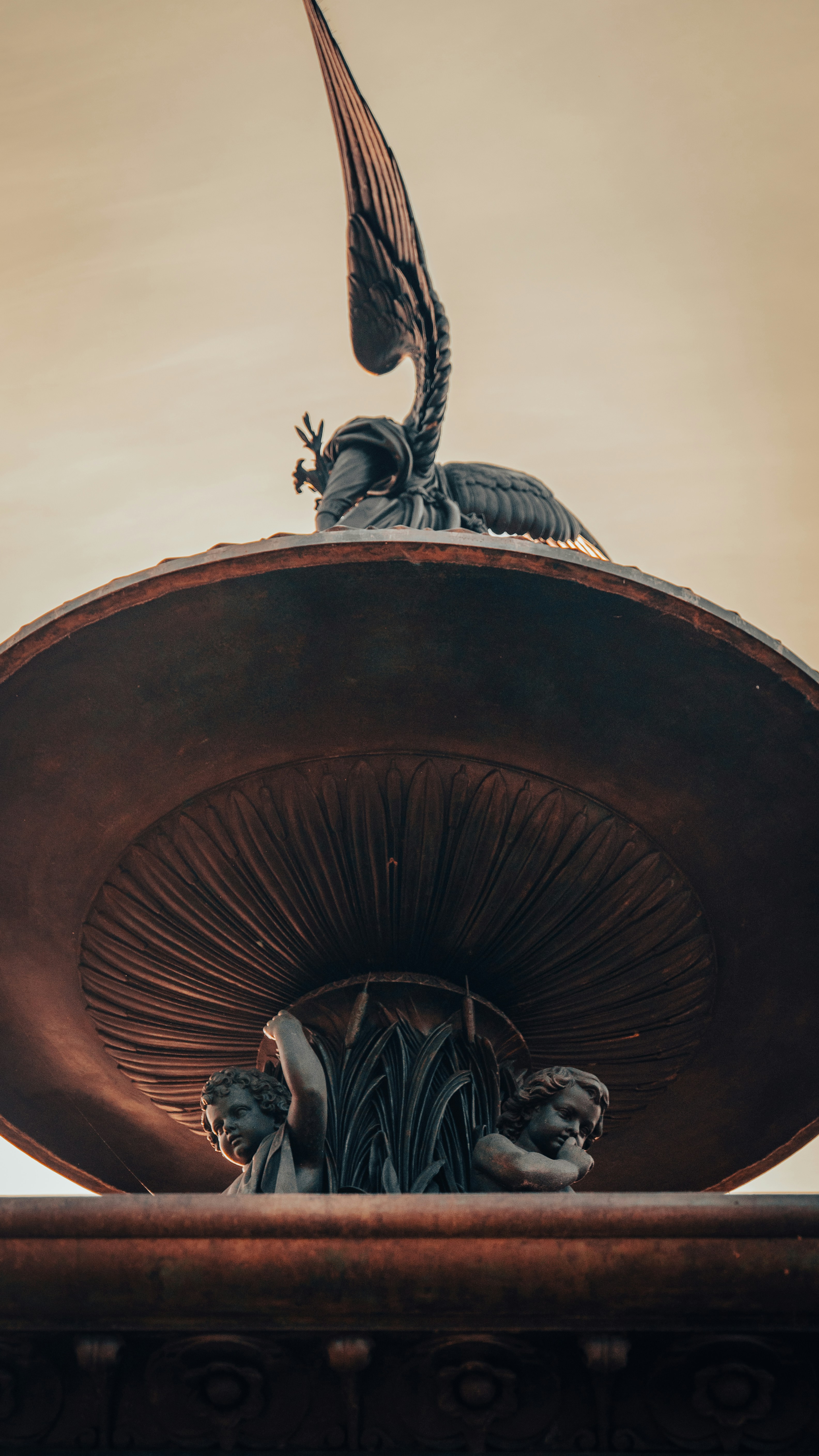 A guardian on the pedestal: winged figure above a sculpted basin