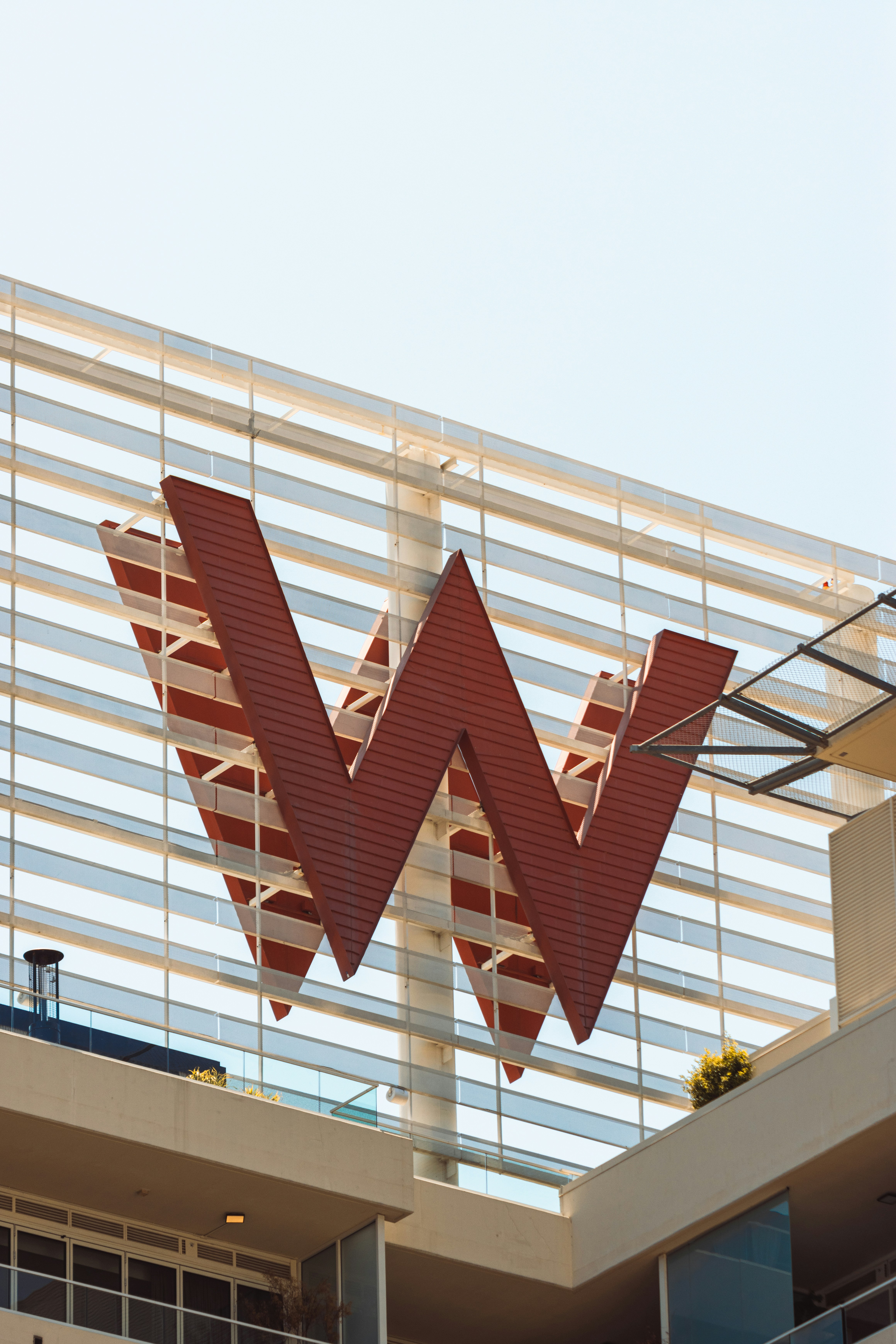 Giant red W over a modern building, framed against a pale sky