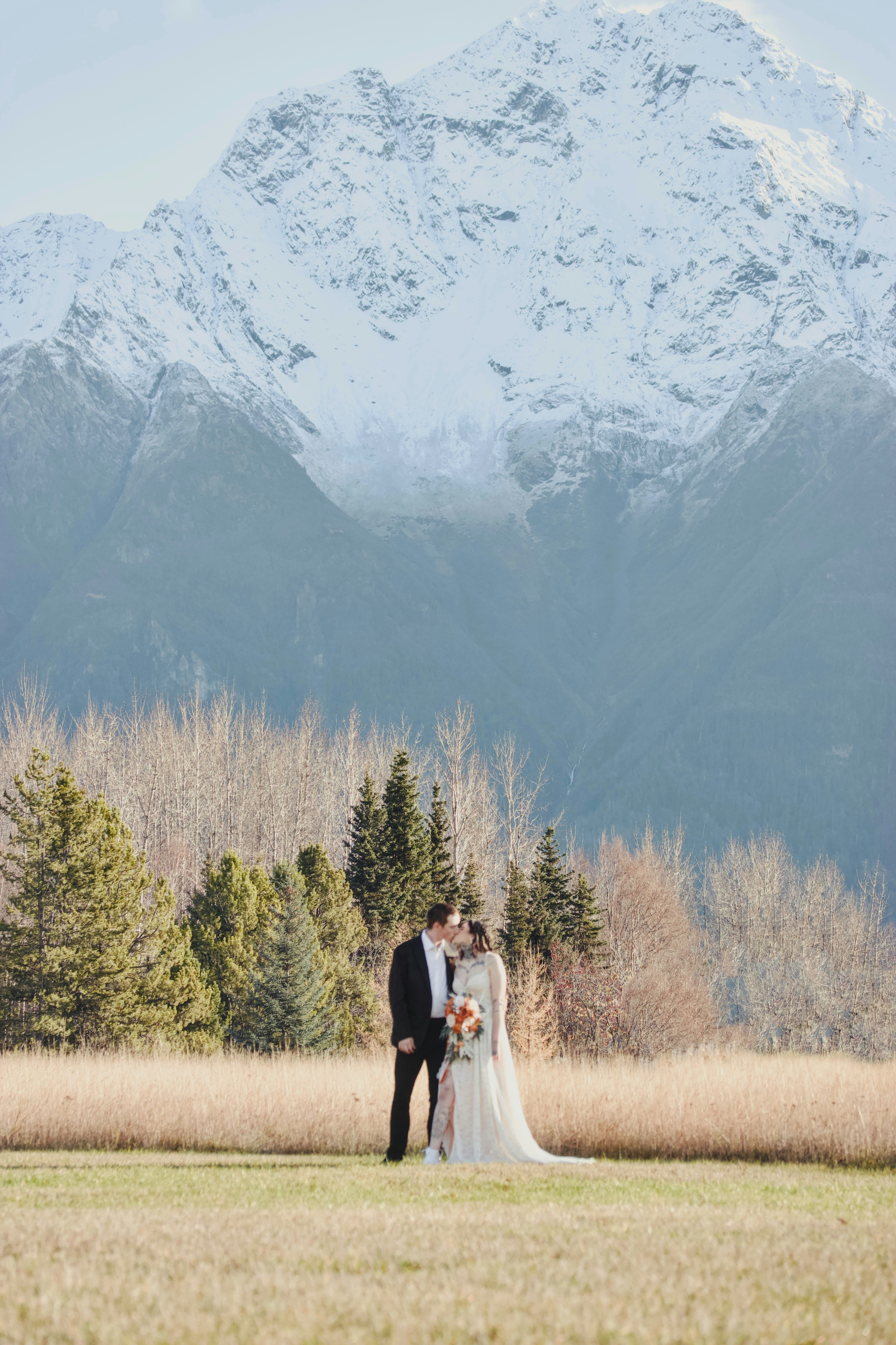 Mountain Vows: A Bride and Groom Stand Against Snowbound Peaks