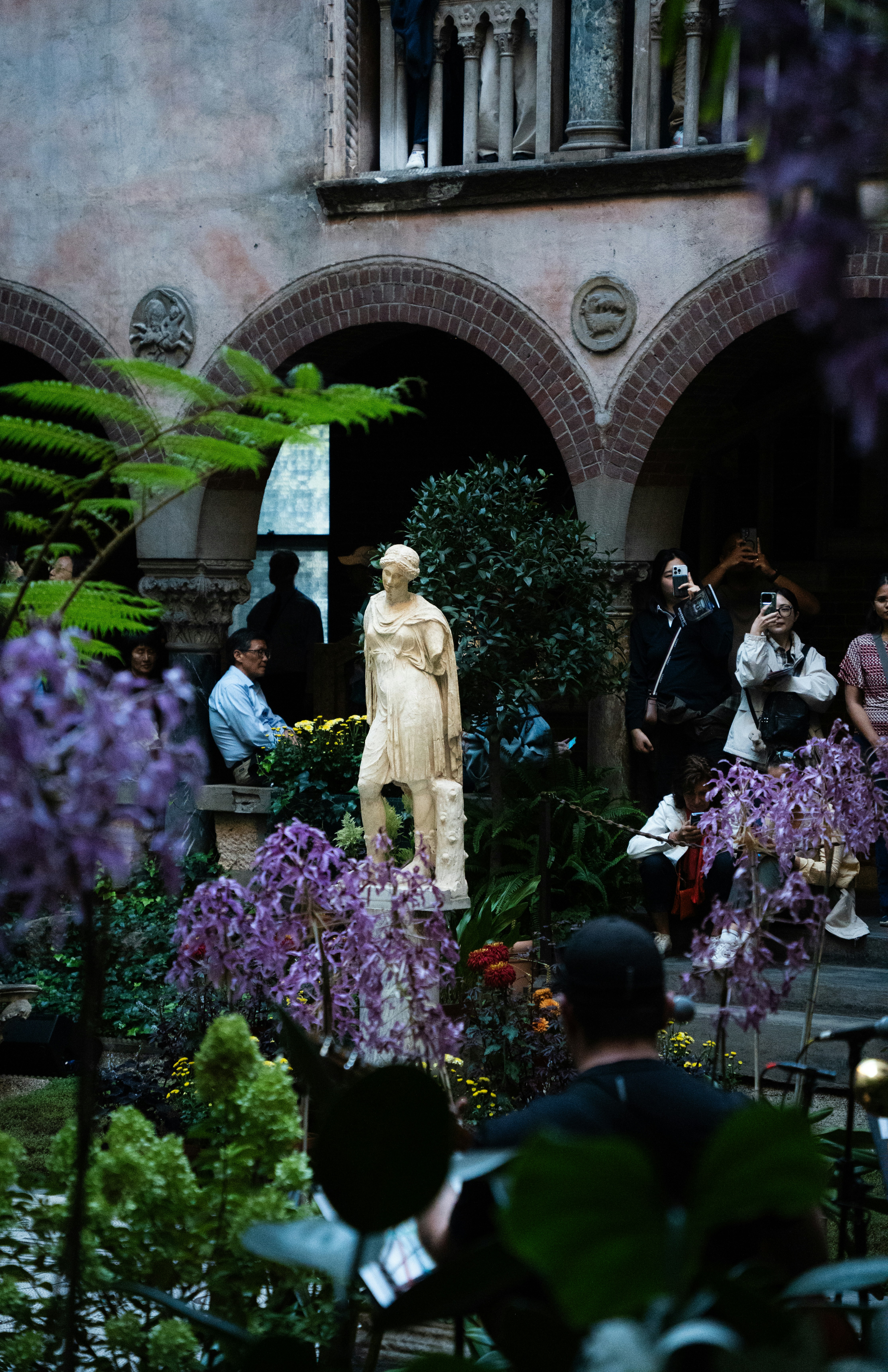Statue in a Courtyard Garden Framed by Arches and Dusky Visitors