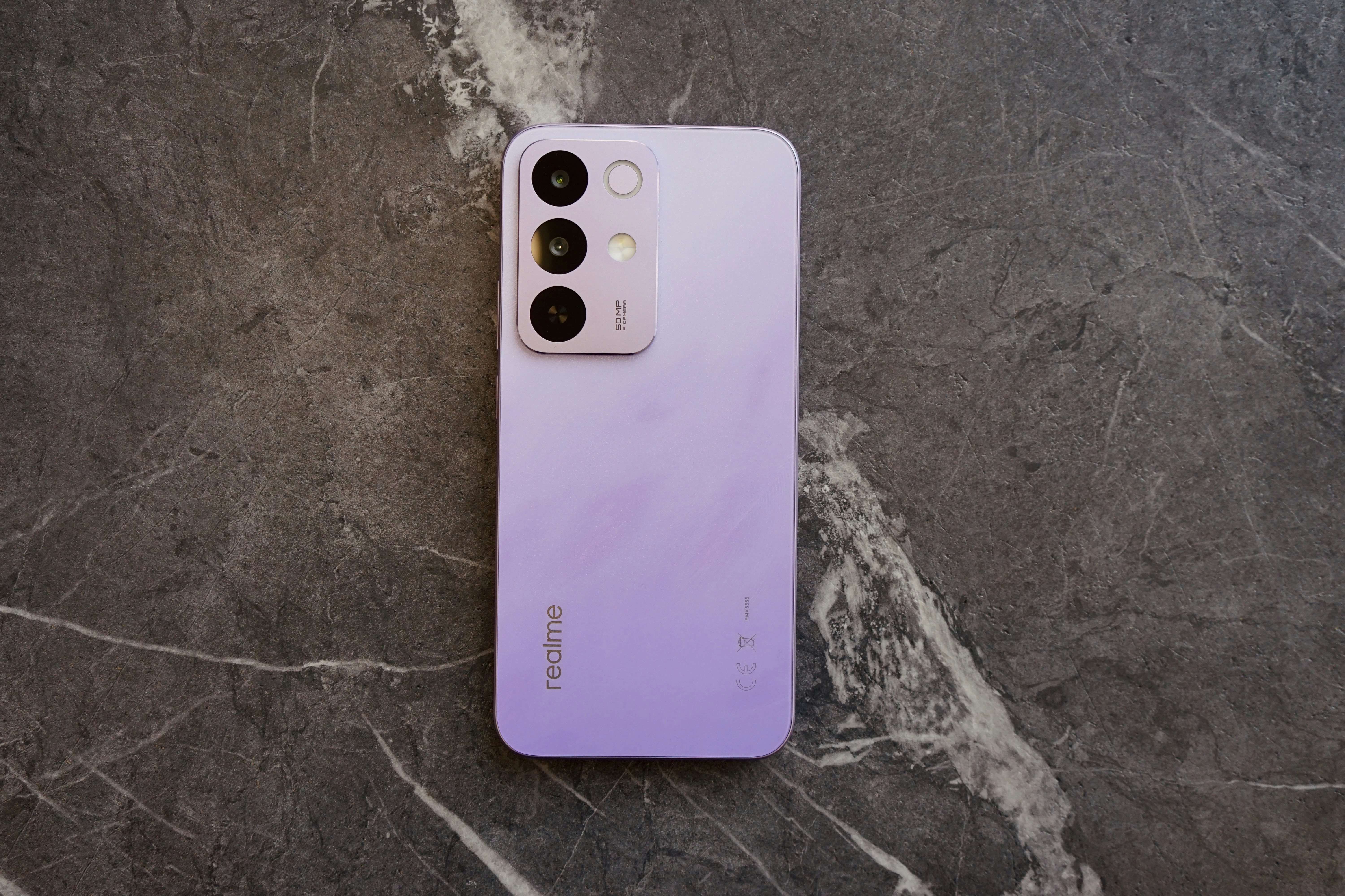 Iridescent Realme: Lavender back of a smartphone resting on a marble surface