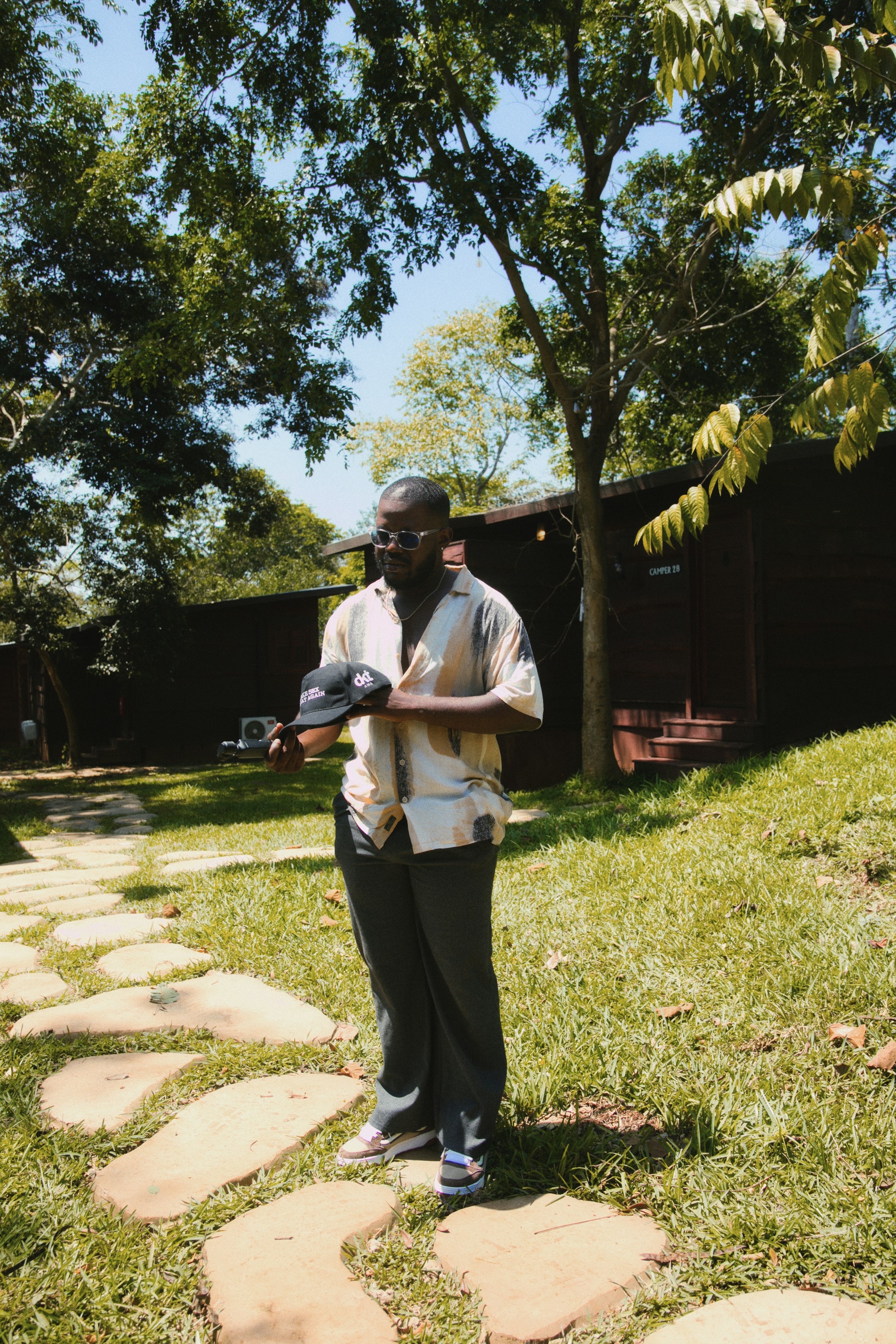 Sunlit Casual Moment: Man Adjusting a Cap in a Park