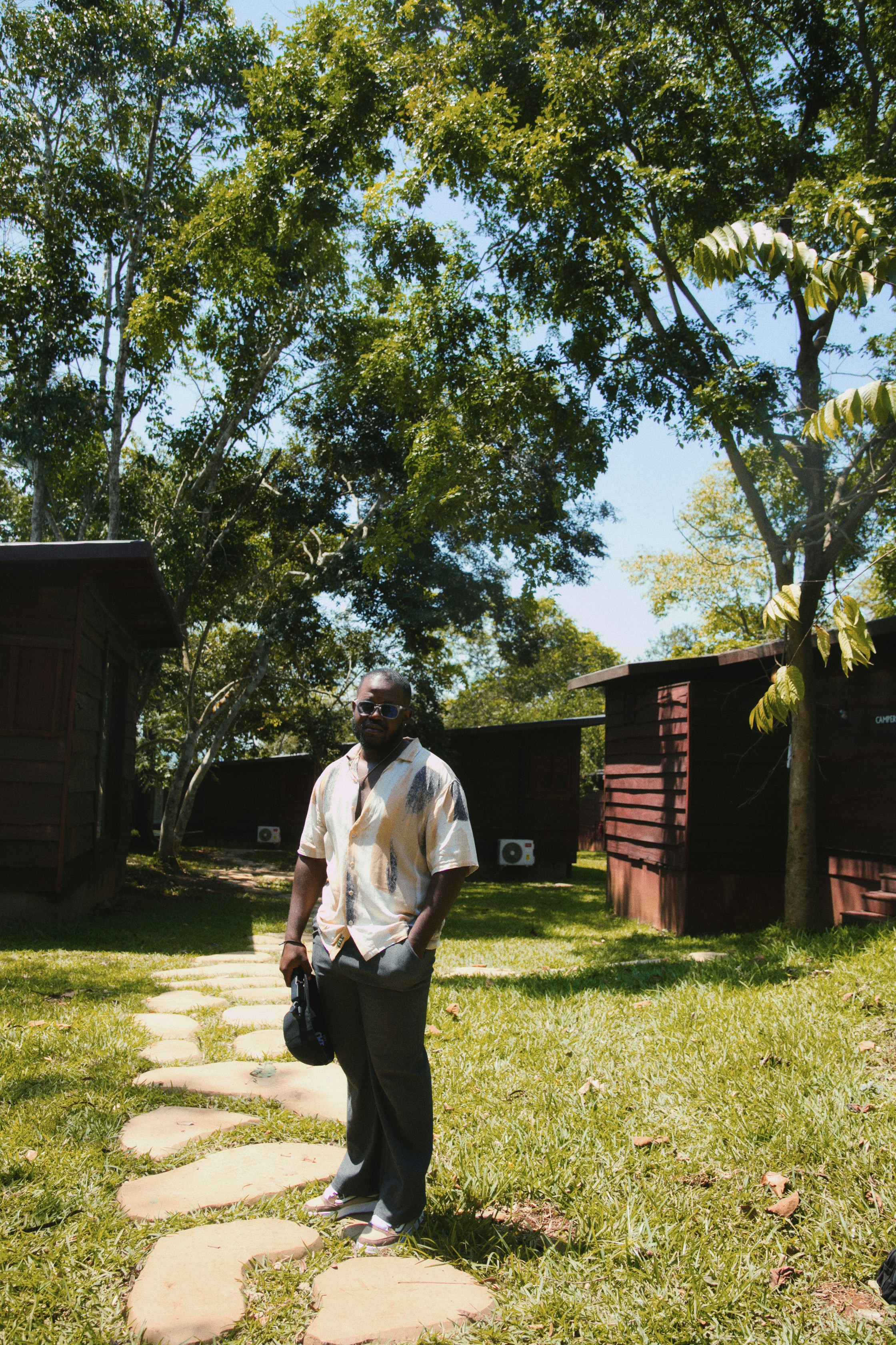 Portrait in a sunlit village yard beneath leafy canopies