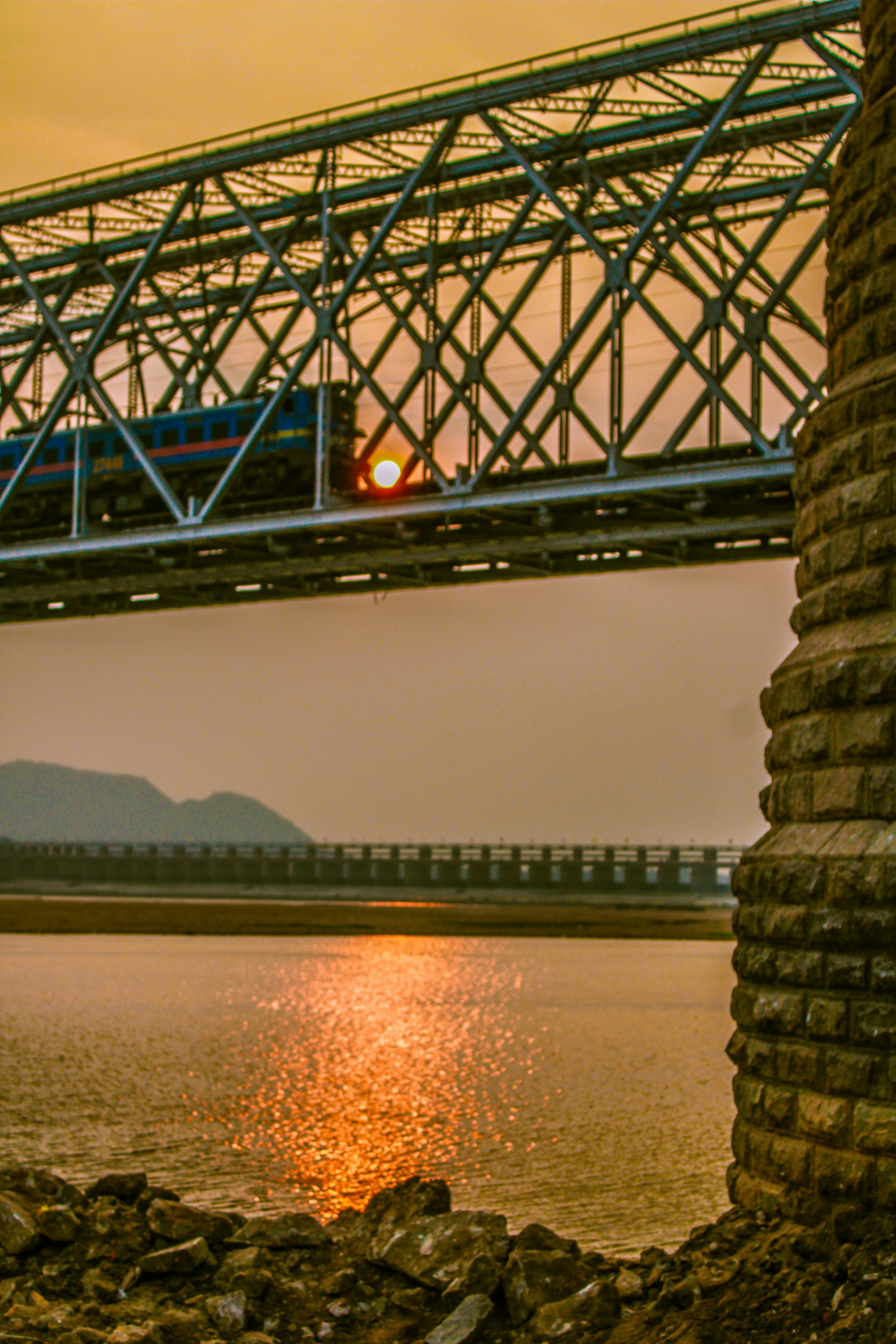 Sunlit Gateway: A Steel Truss Bridge Framed by Stone Pillars