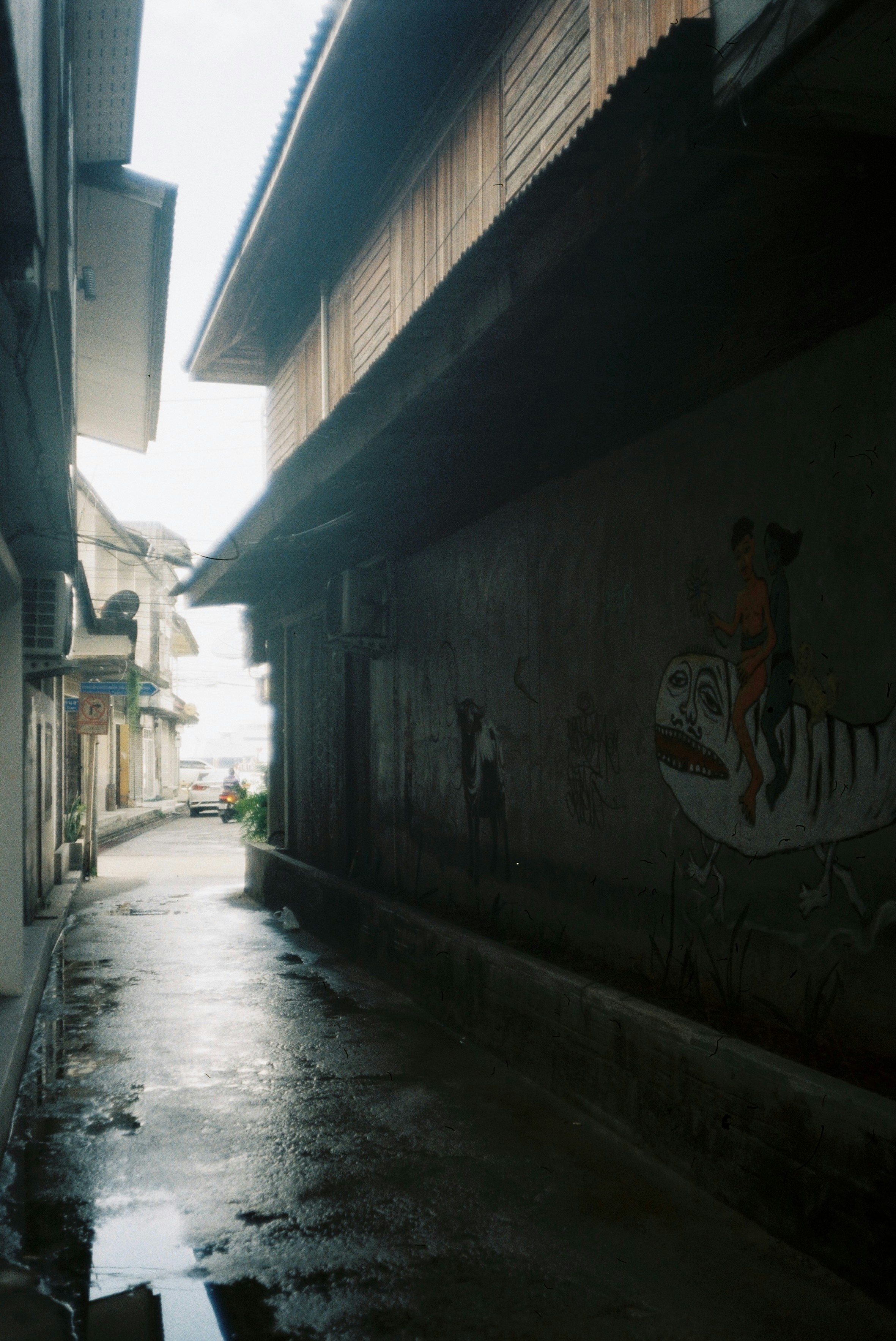 Narrow Alleyway Between Sunlit Rooflines and Graffiti On the Wall