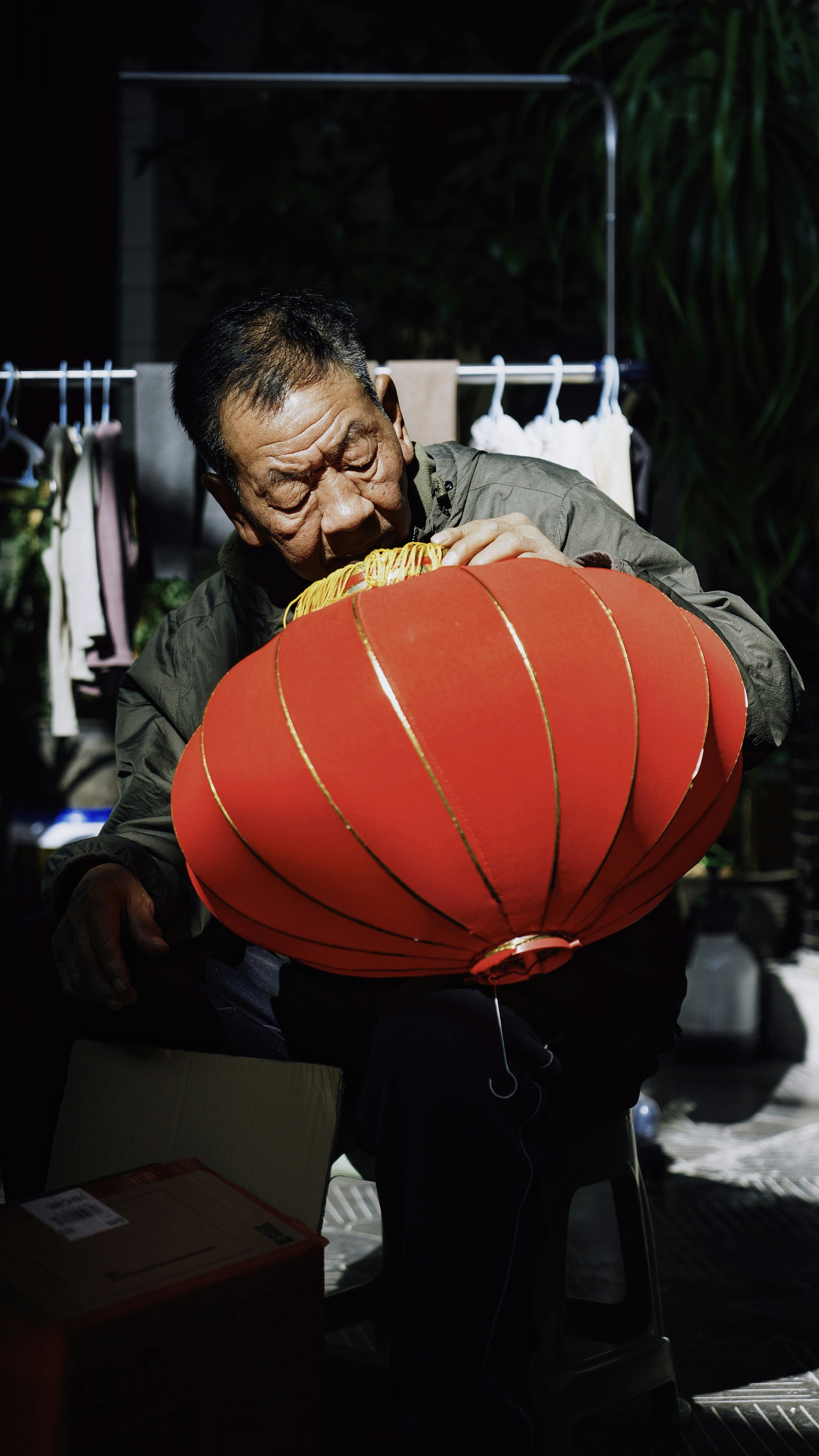 Hands shaping the glow: a craftsman with a red lantern under night skies