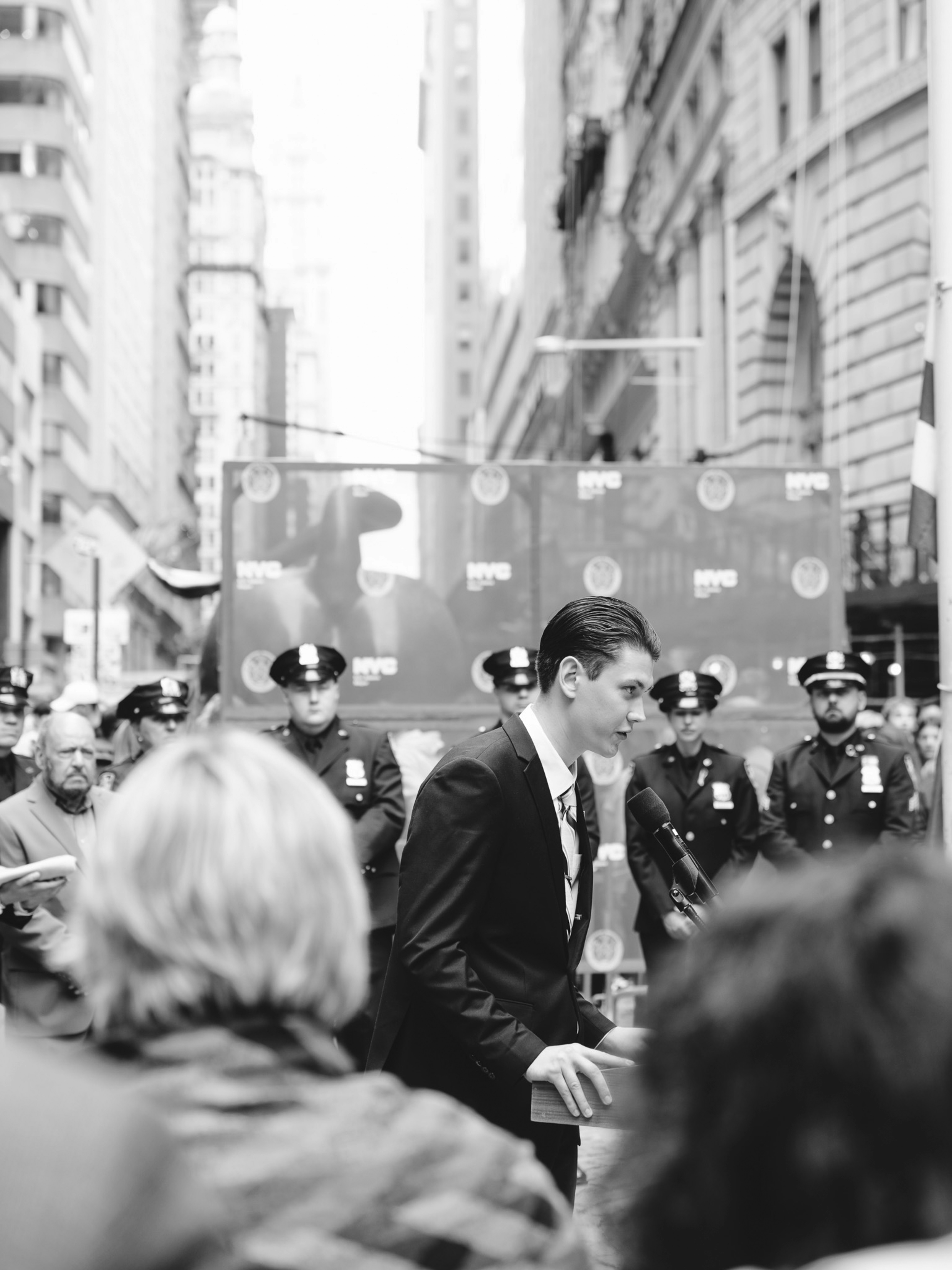Proceedings in the City: a poised speaker before a disciplined ensemble