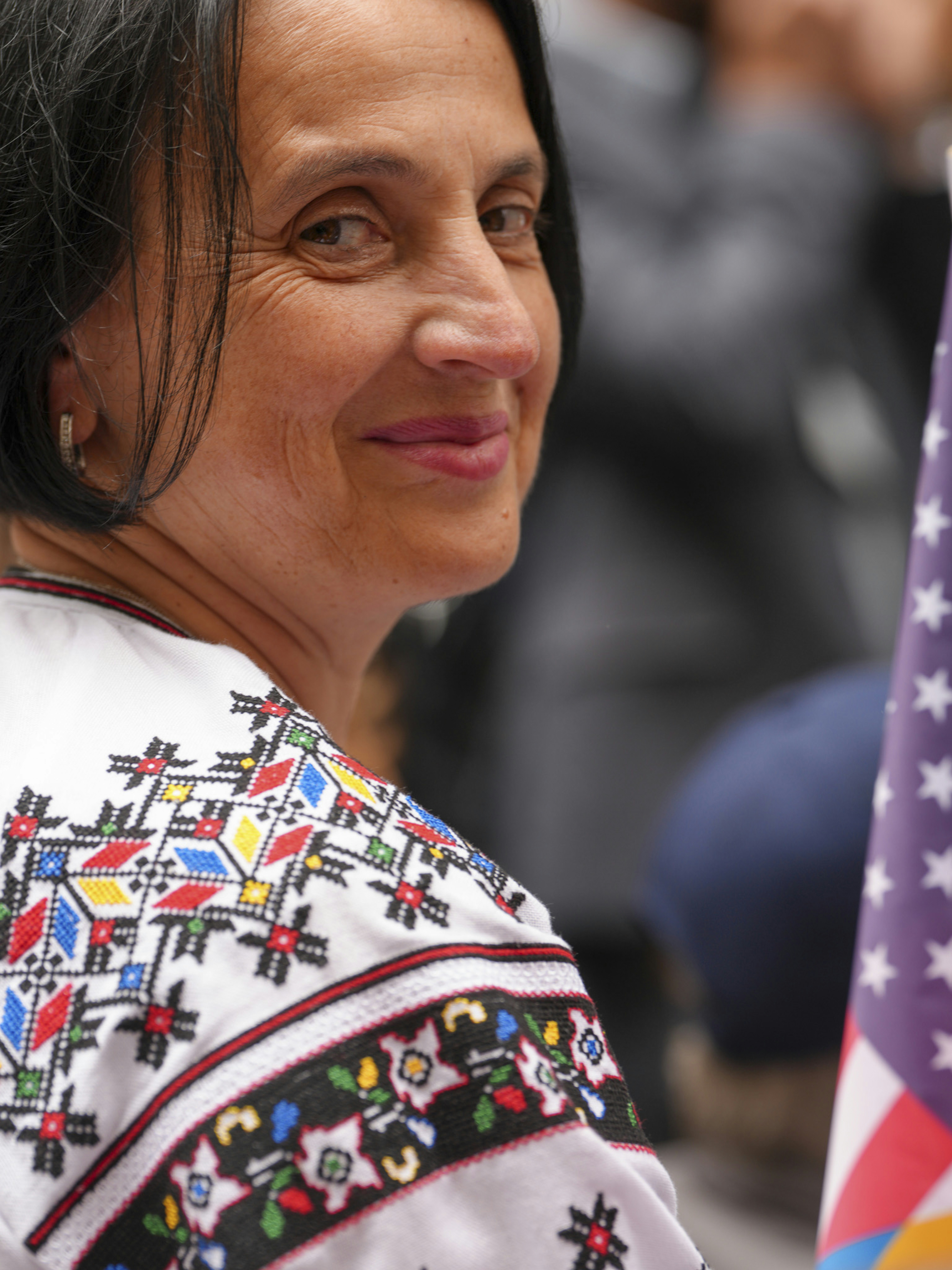A Ukrainian rally unfolds in downtown Manhattan, where community members, NYC officials, and uniformed police gather in solidarity. A woman draped in a blue and yellow flag stands solemnly among the crowd, while a young attendee holds a folded Ukrainian flag during a formal civic ceremony. The event reflects unity, patriotism, and public support for Ukraine in the heart of New York City. Captured by Olek Buzunov @buzunov.photoart, documenting moments of resilience and civic engagement.