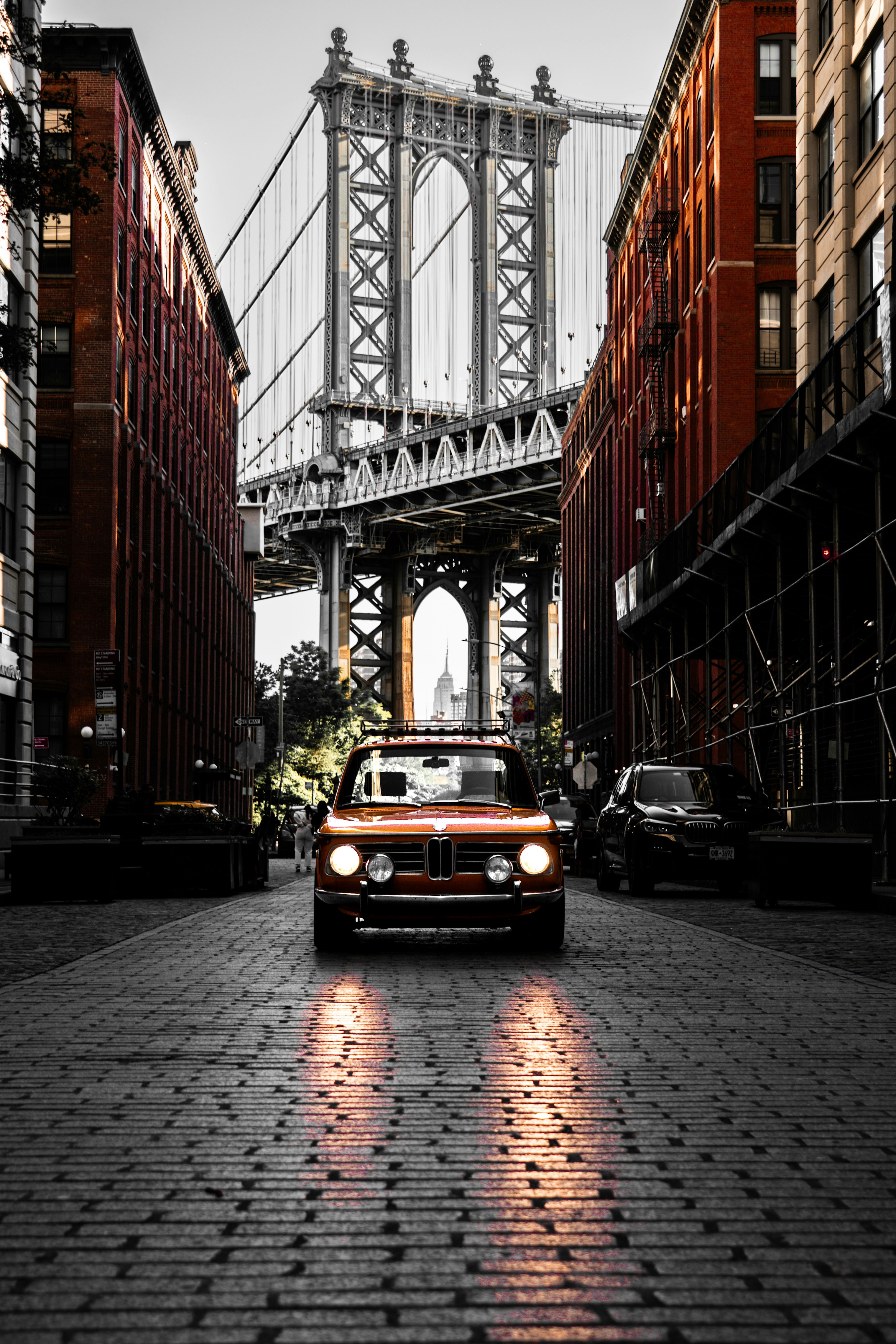 Toward the Span: A Red Taxi Leads the Way Under the City Bridge