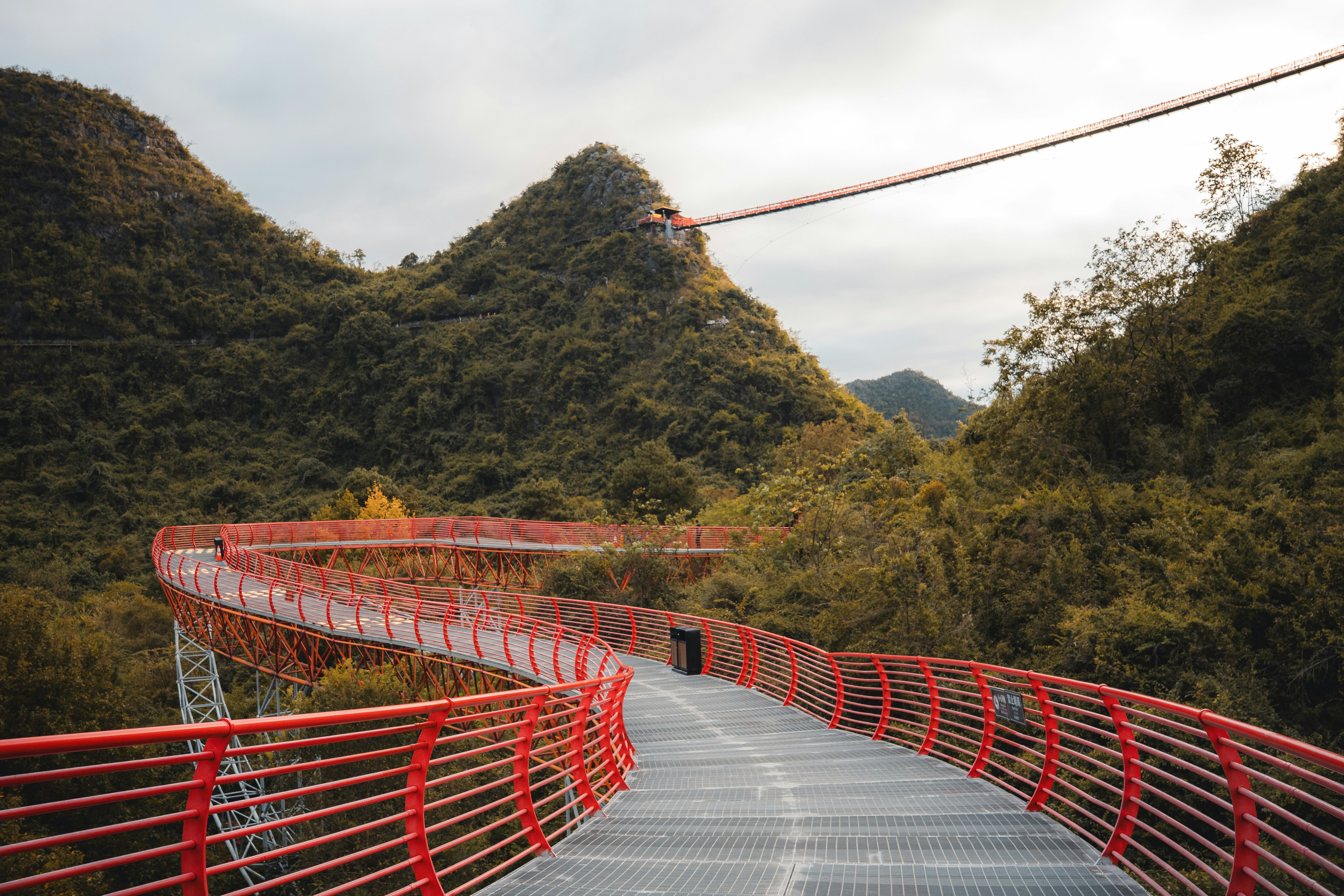 Red Skyline: A Curved Bridge Threading the Mountain Veil